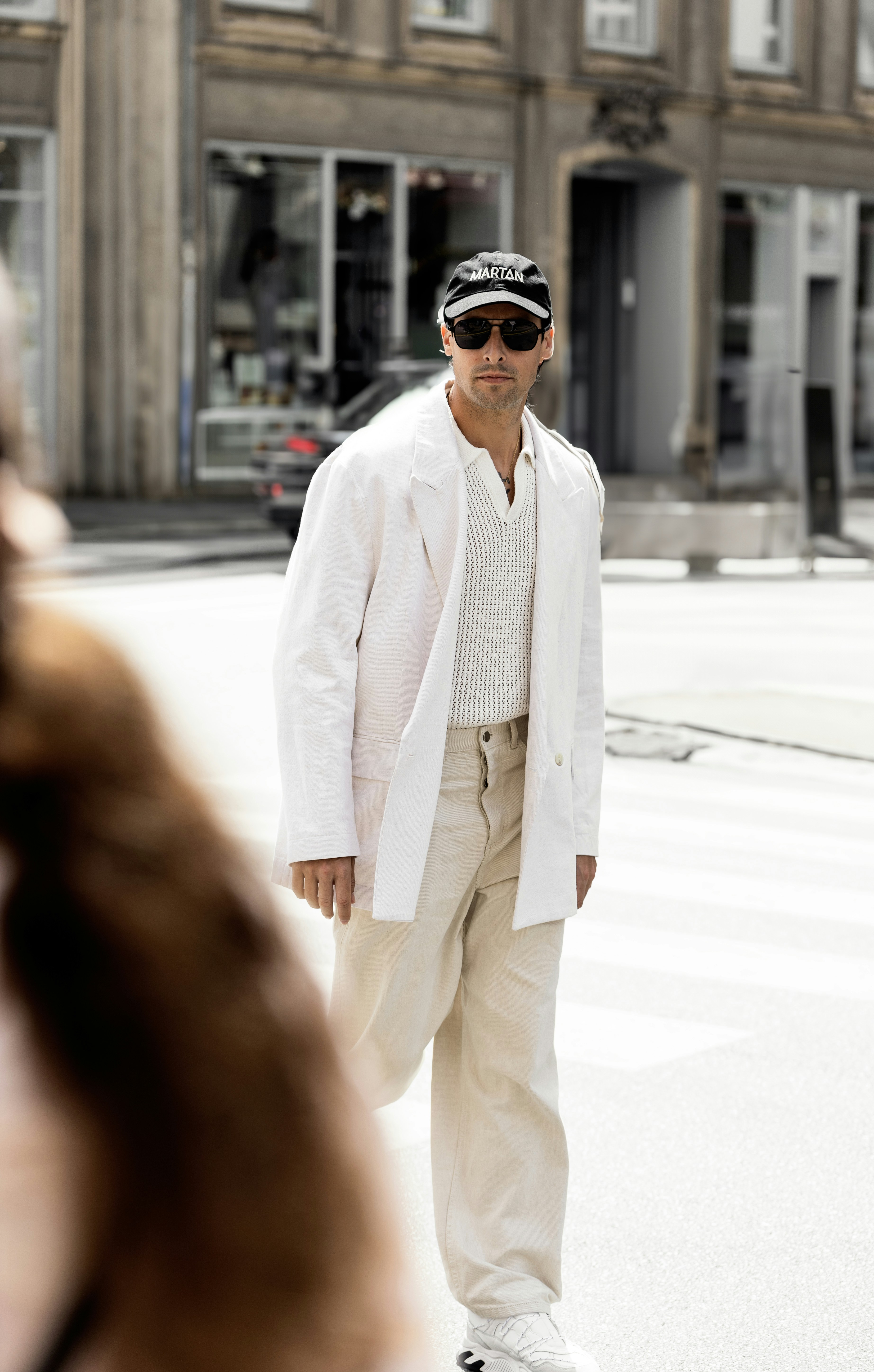 Street-Scene Minimalist: A man in white suit steps across a sunlit crosswalk