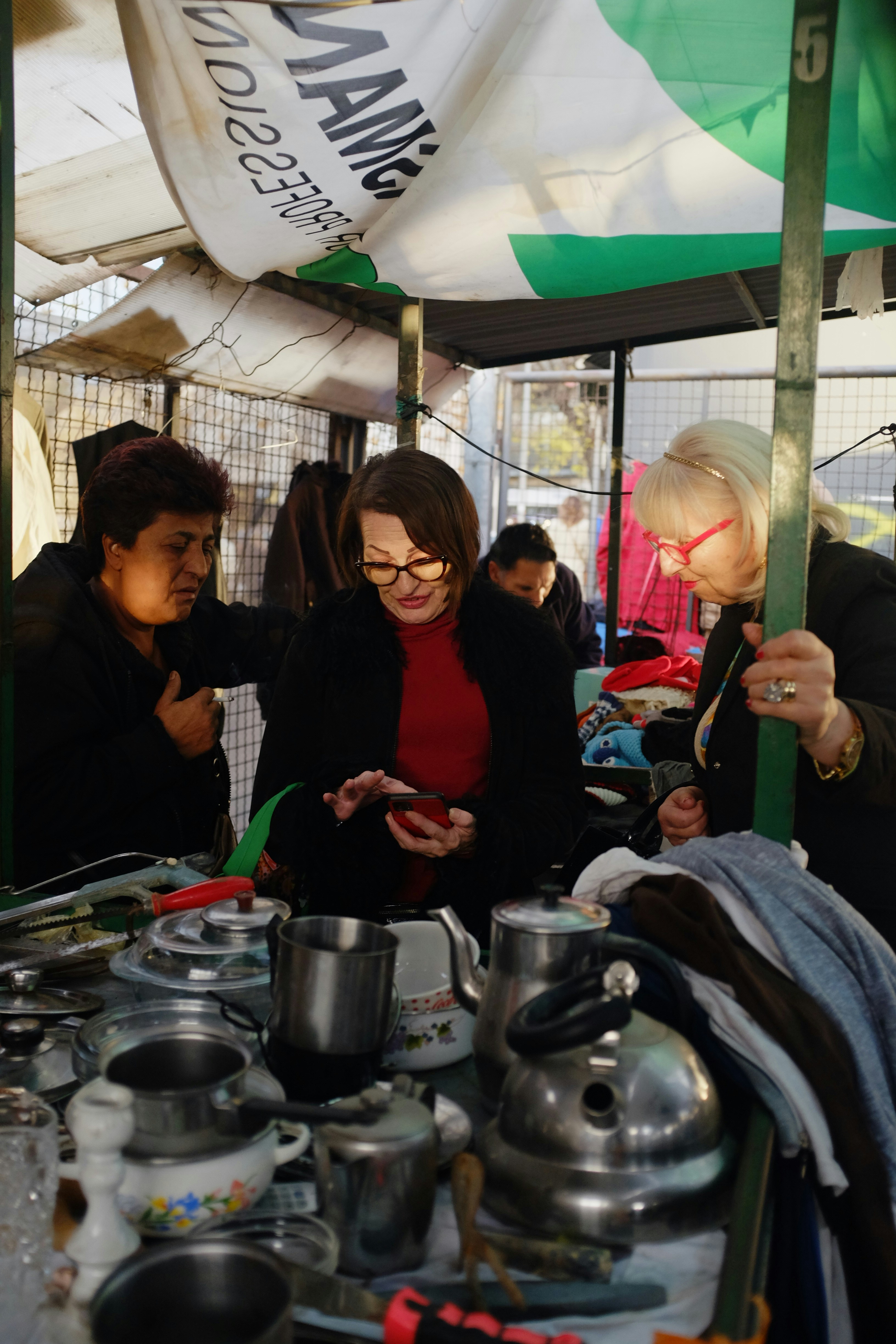 Red-Topped Moment at a Market Stall Among Kettles and Conversation