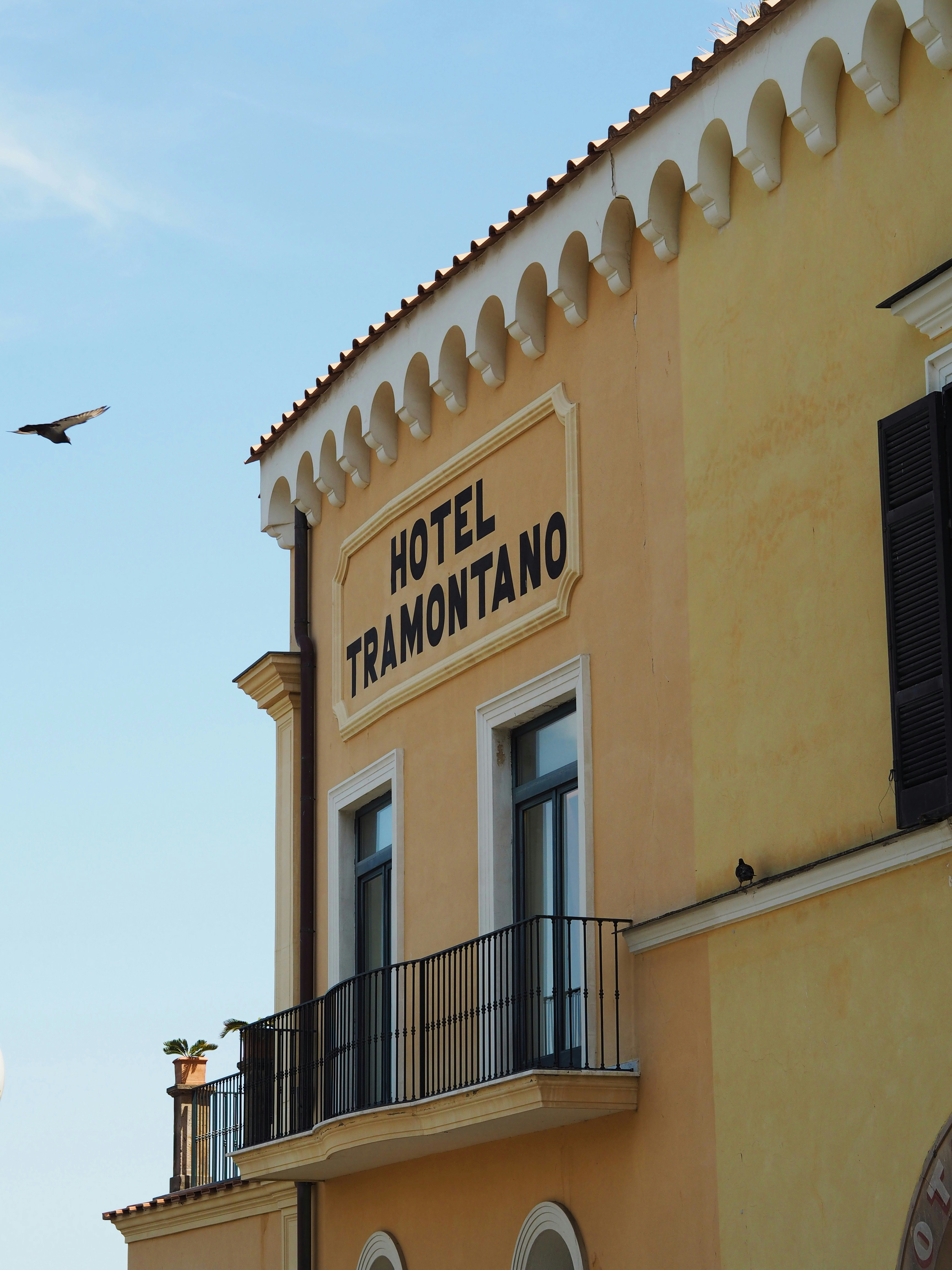Sunlit Yellow Facade of Hotel Tramontano under a Calm Blue Sky