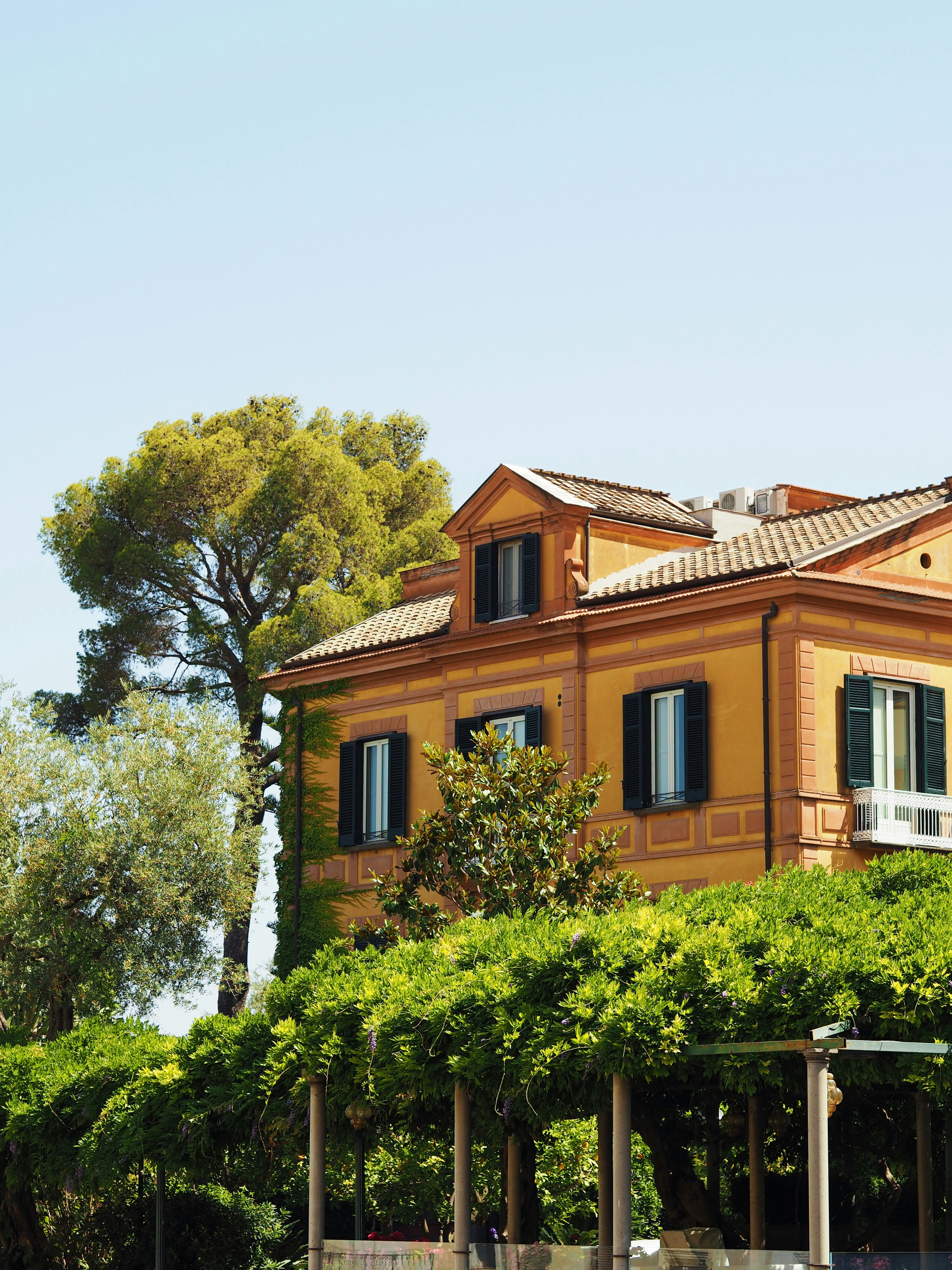 Terracotta Villa Rising Through Greenery Under a Clear Blue Sky