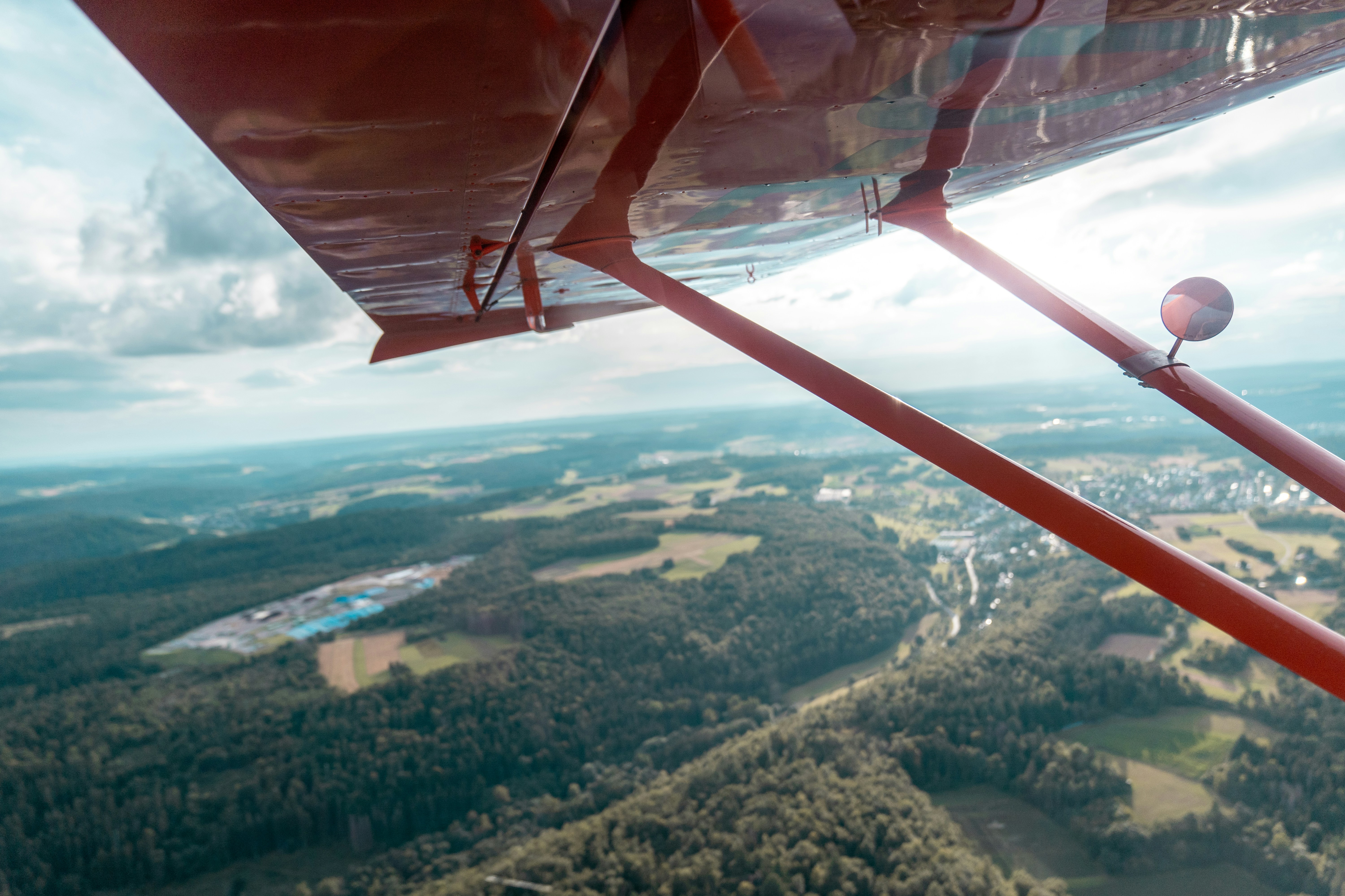 Quilted Skies: Red Wing Tracing Through Patchwork Fields