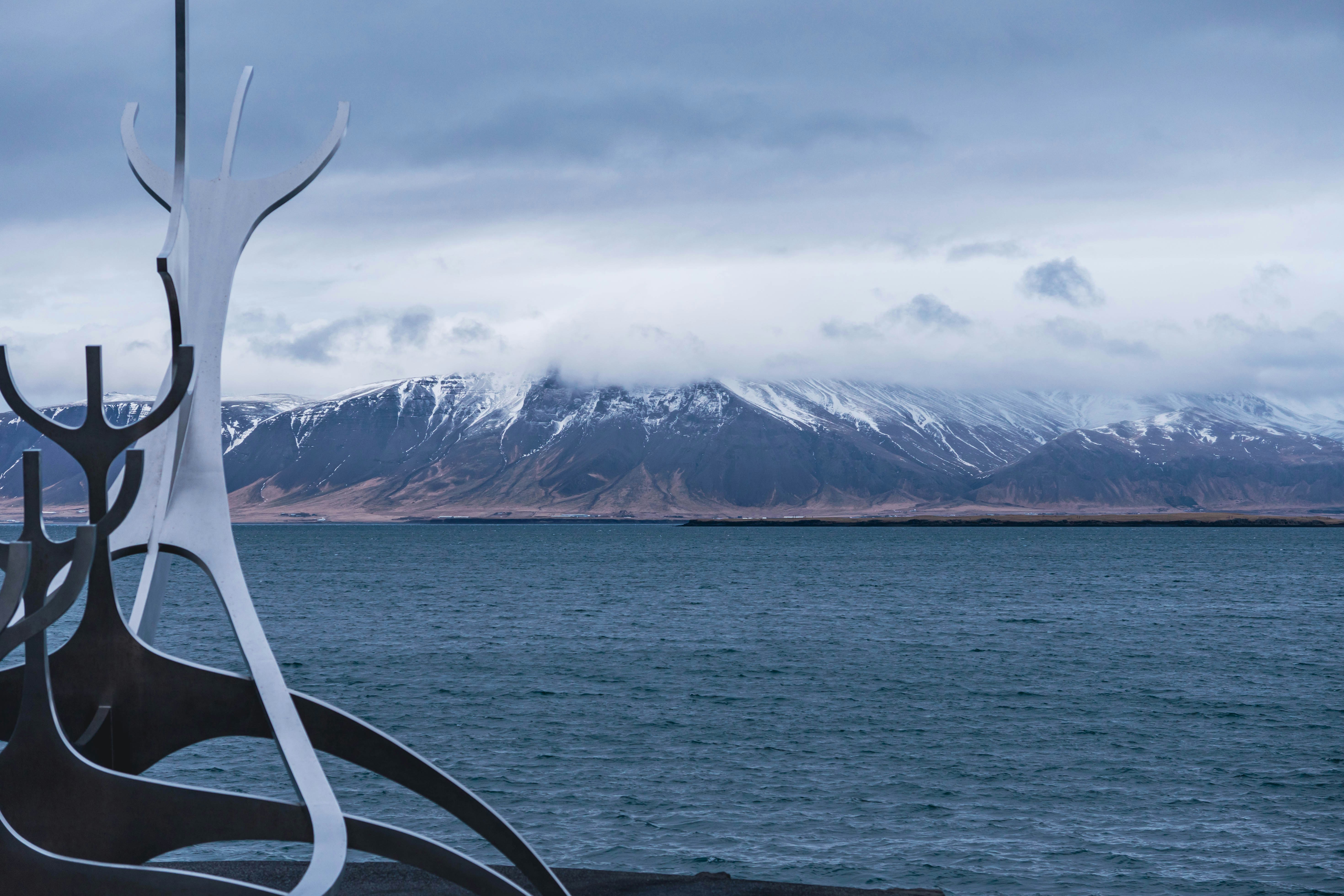 Sun Voyager at Faxaflói: A White Sail Framed by a Snow-Kissed Icelandic Fjord