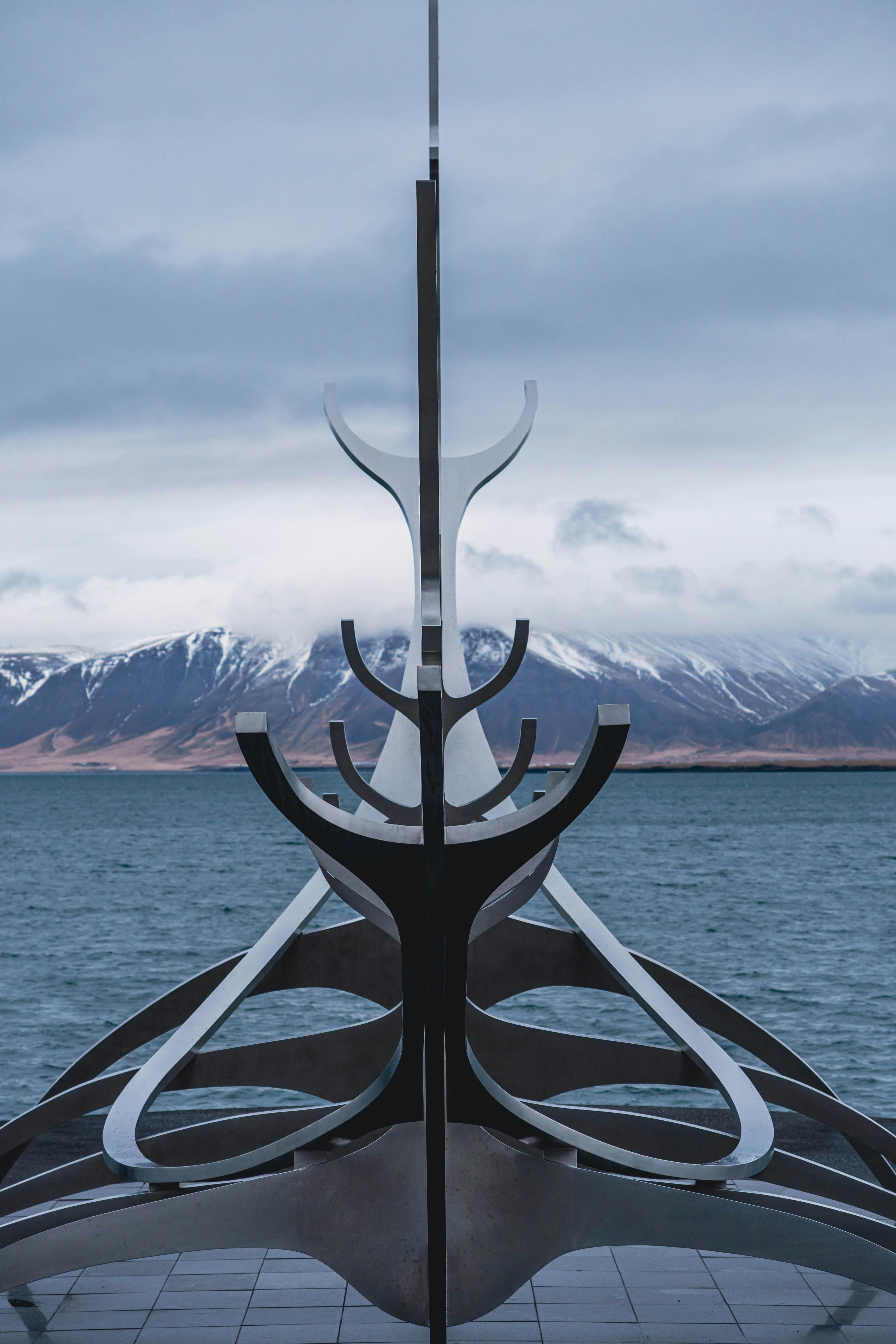 Mirror-Arch at Sea: Symmetrical Stainless Sculpture Framing Snowy Horizons