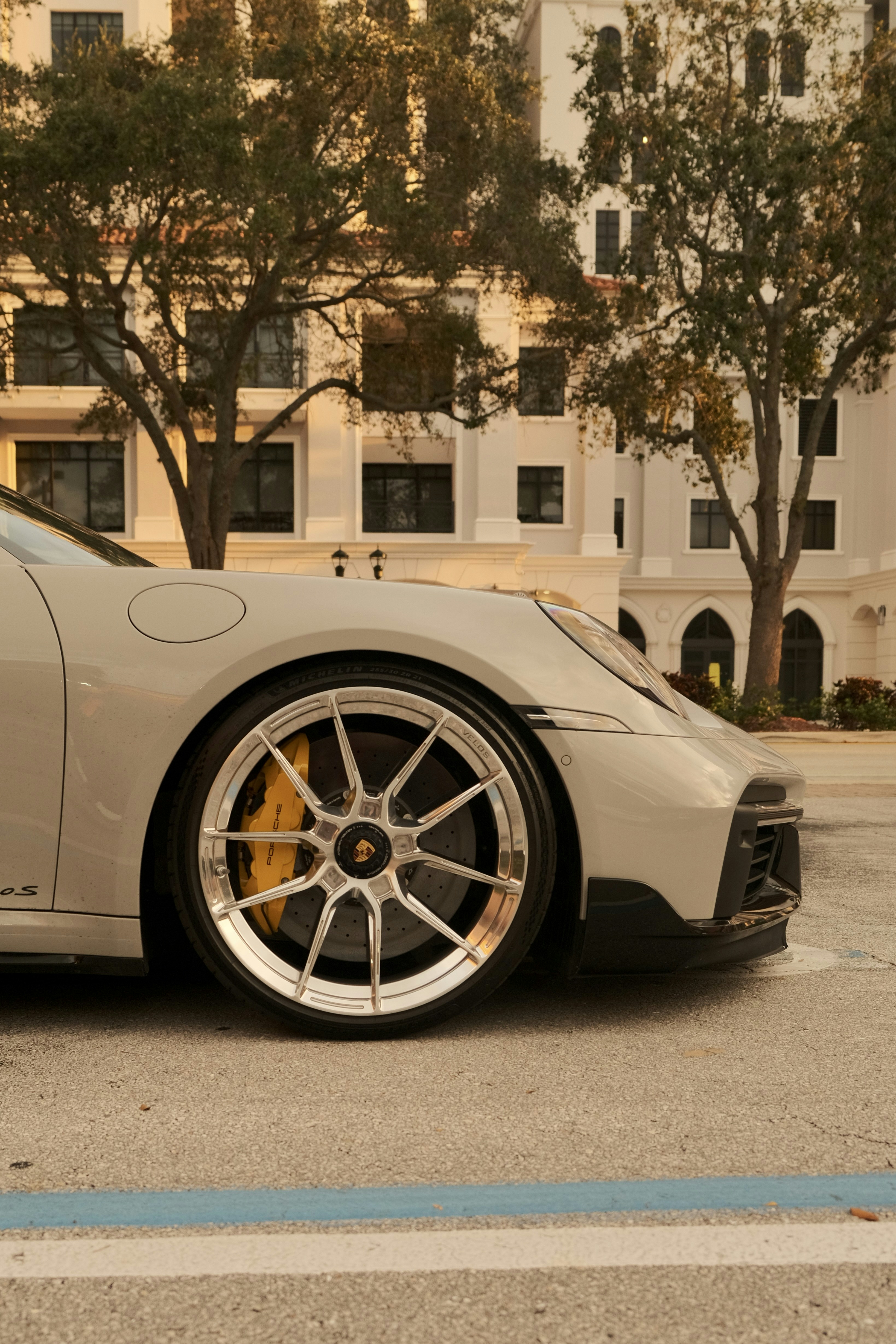 Chrome Spokes and Golden Brakes: A Porsche in Sunlit Parking