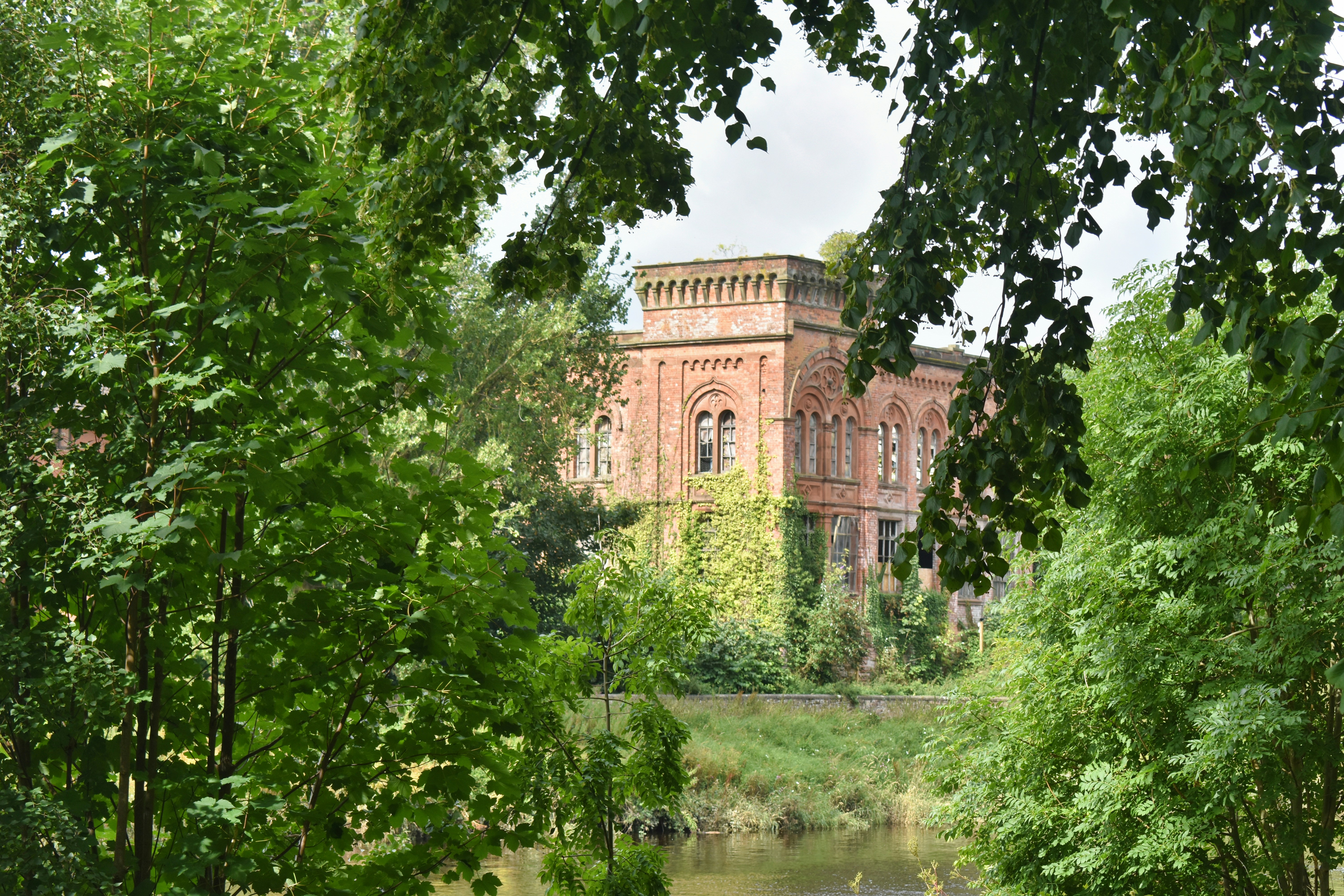 Brick mansion peeking through emerald arches by the water