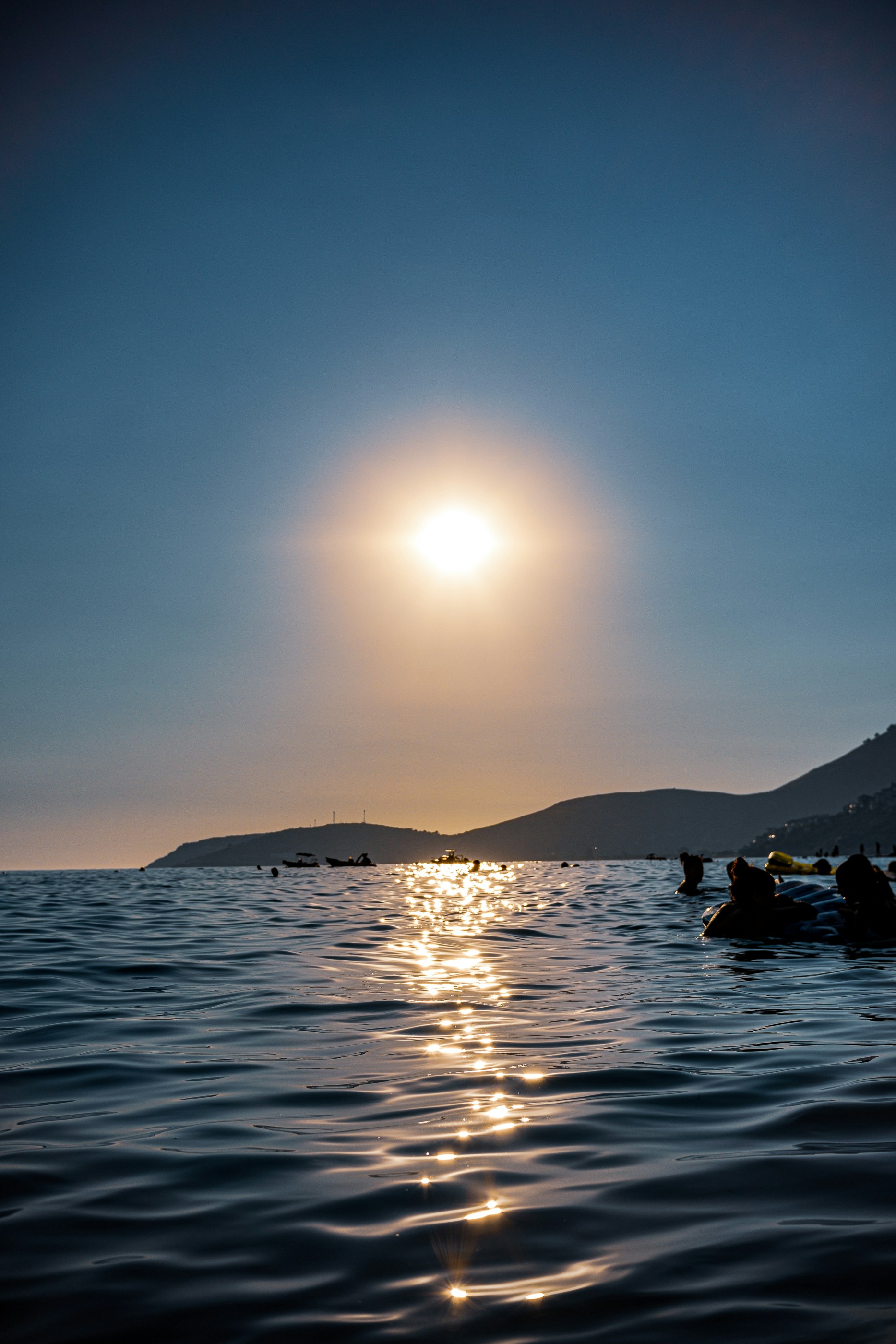 Golden Path Across Quiet Waters: Sunset Silhouettes Along a Distant Shore