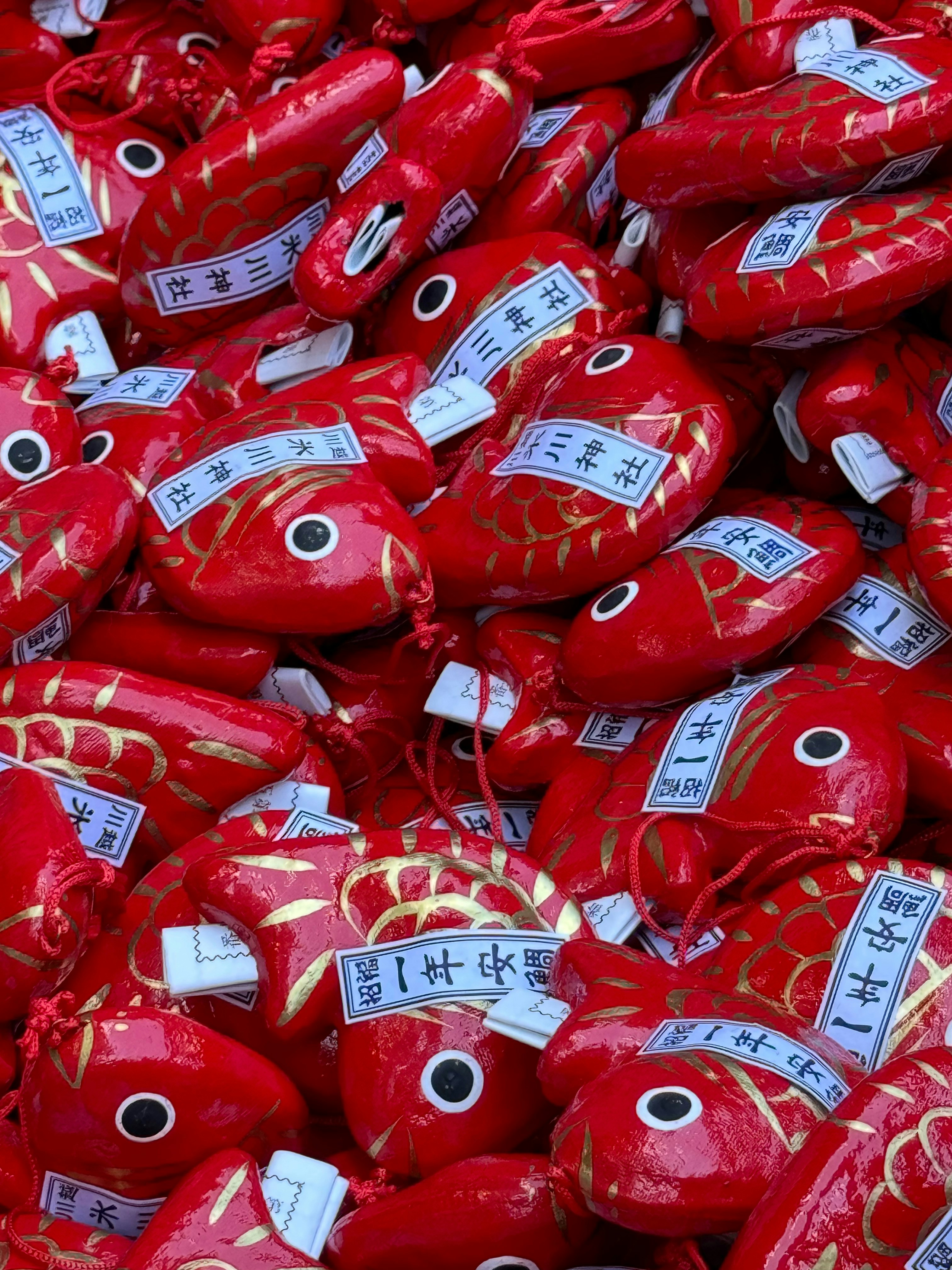 Photograph of a dense pile of red koi-shaped ornaments with white tag labels featuring Chinese characters.