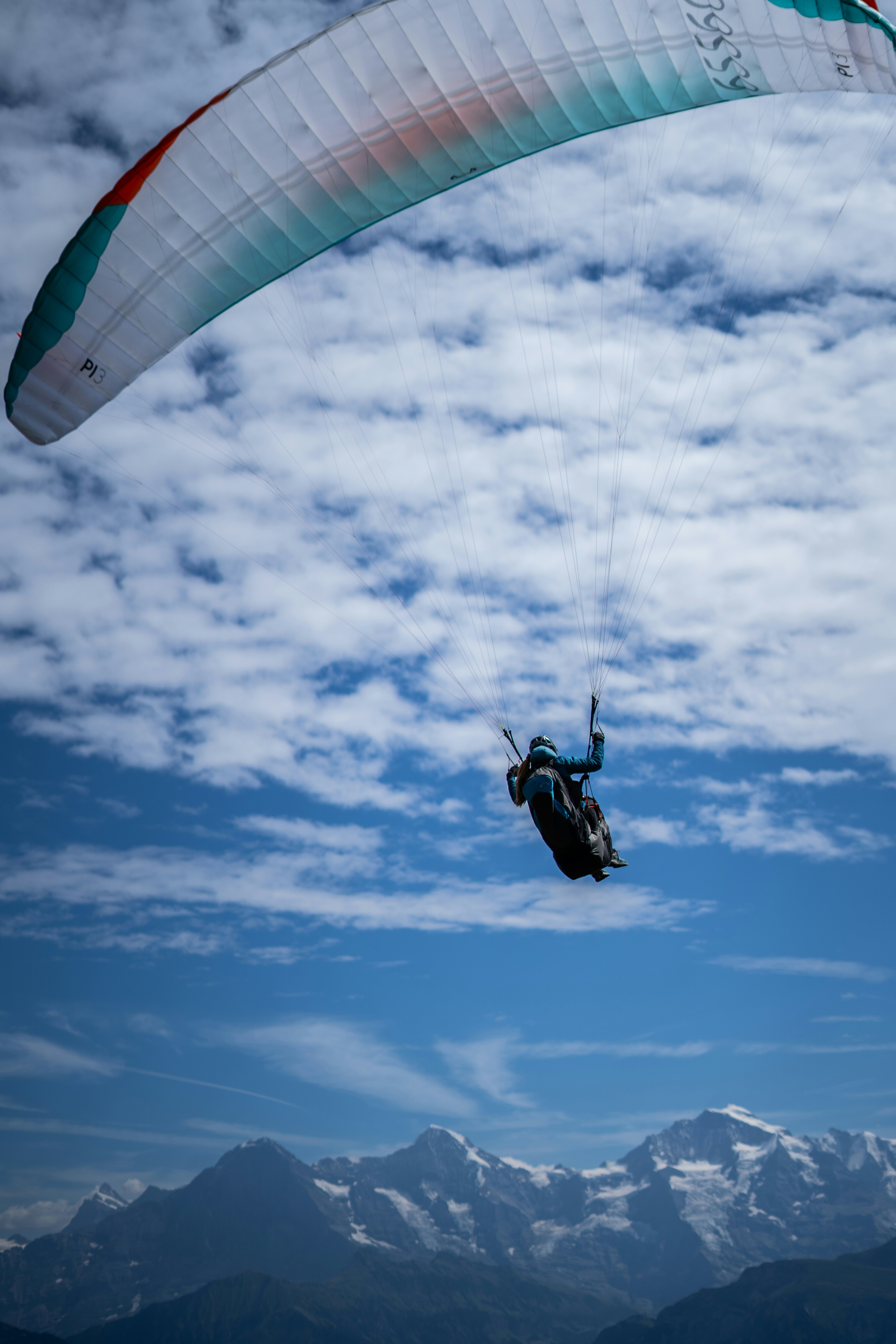 Arc in the Blue: Paraglider sweeping above the Alpine Crest