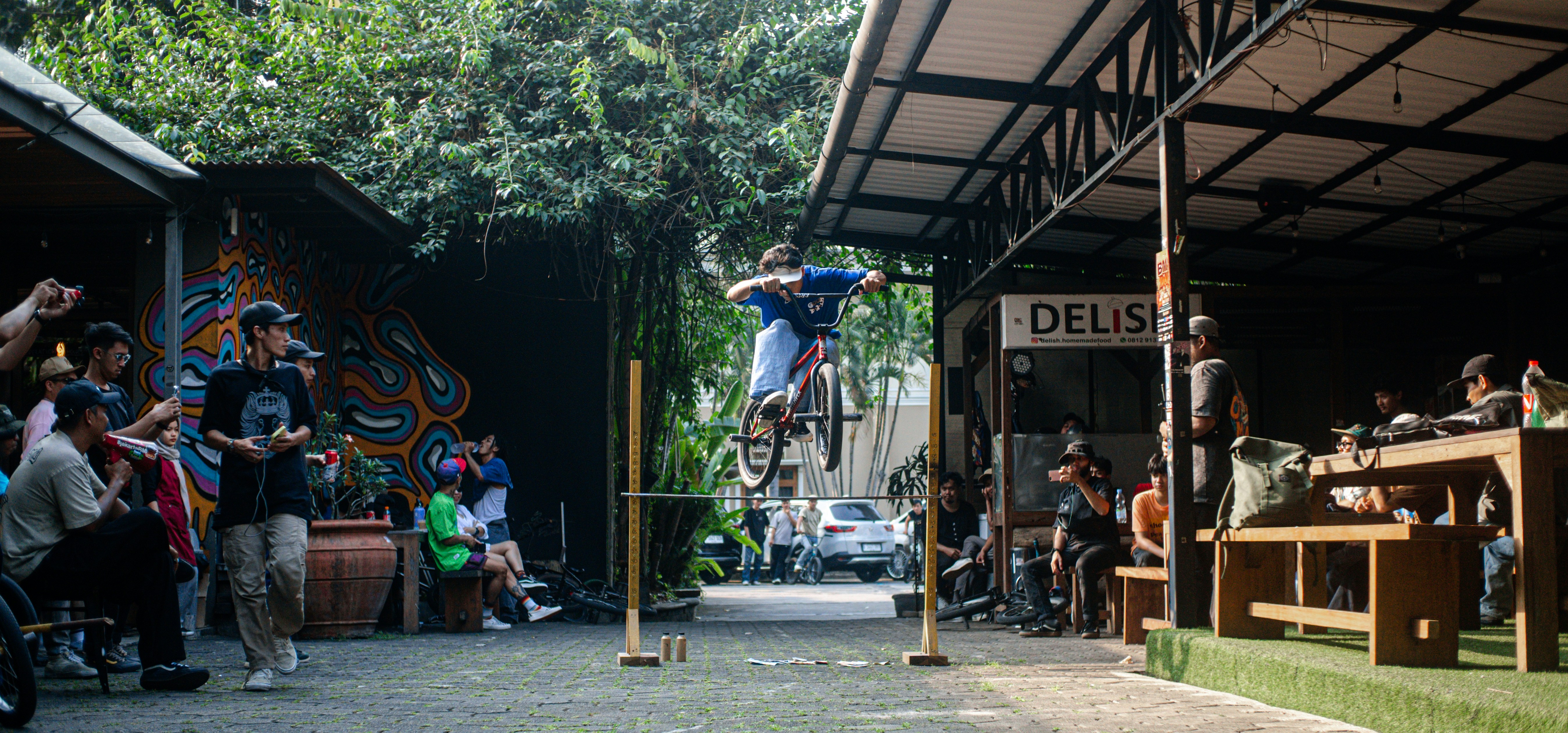 Urban Trial: BMX Aerial over a Wooden Ramp Amid Spectators