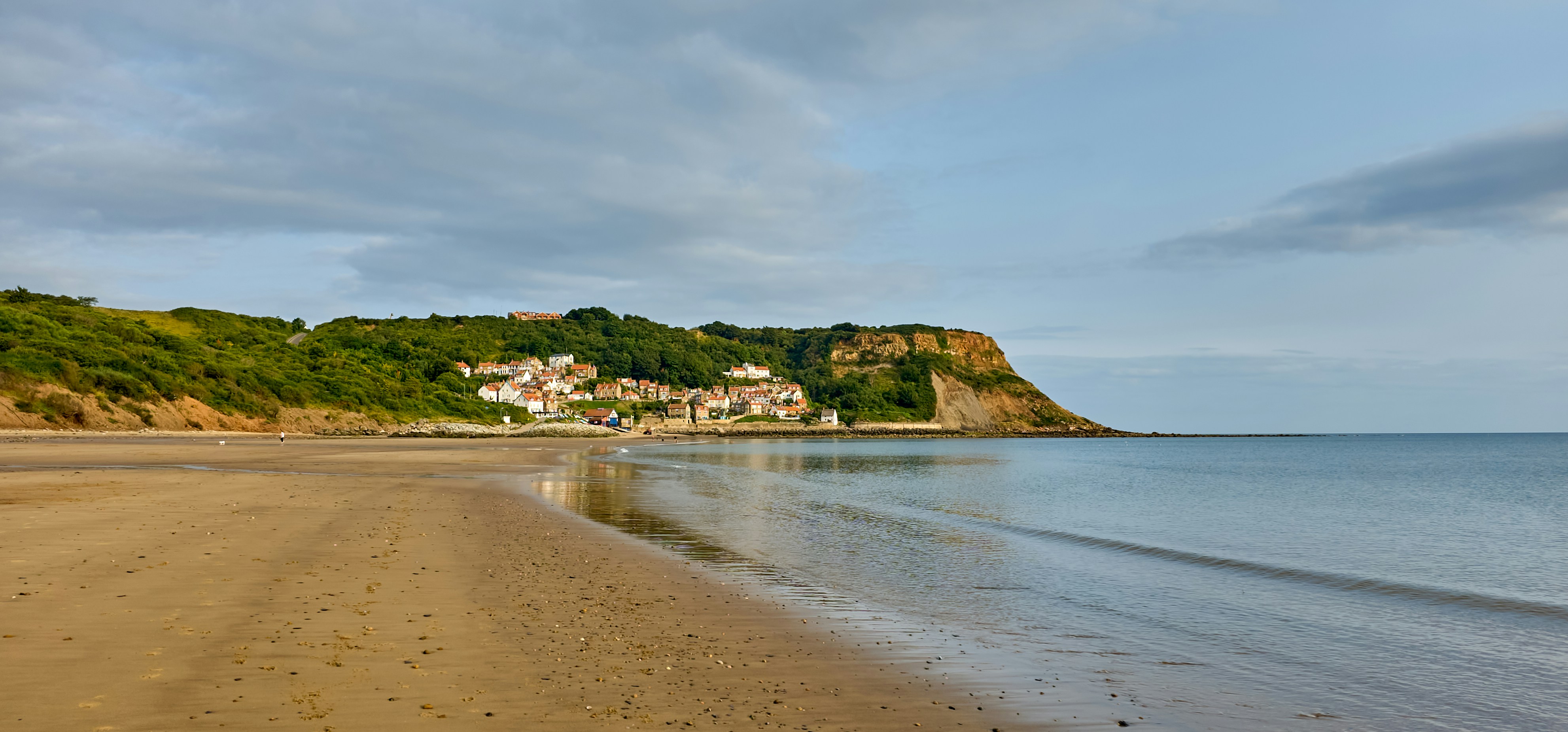 A sandy beach with houses on a hill in the distance photo – Free ...
