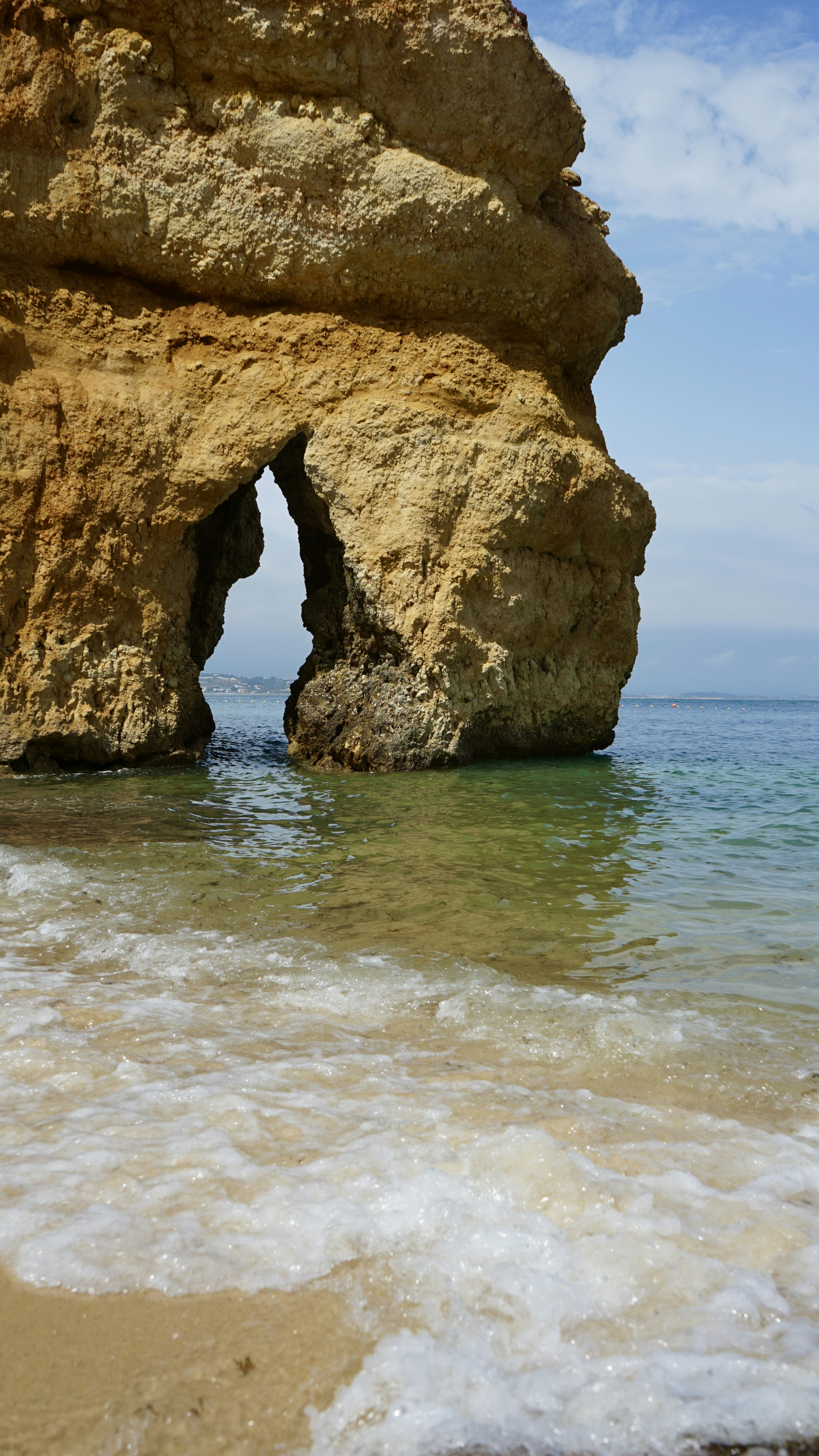 A large rock sticking out of the ocean next to a beach photo – Free ...