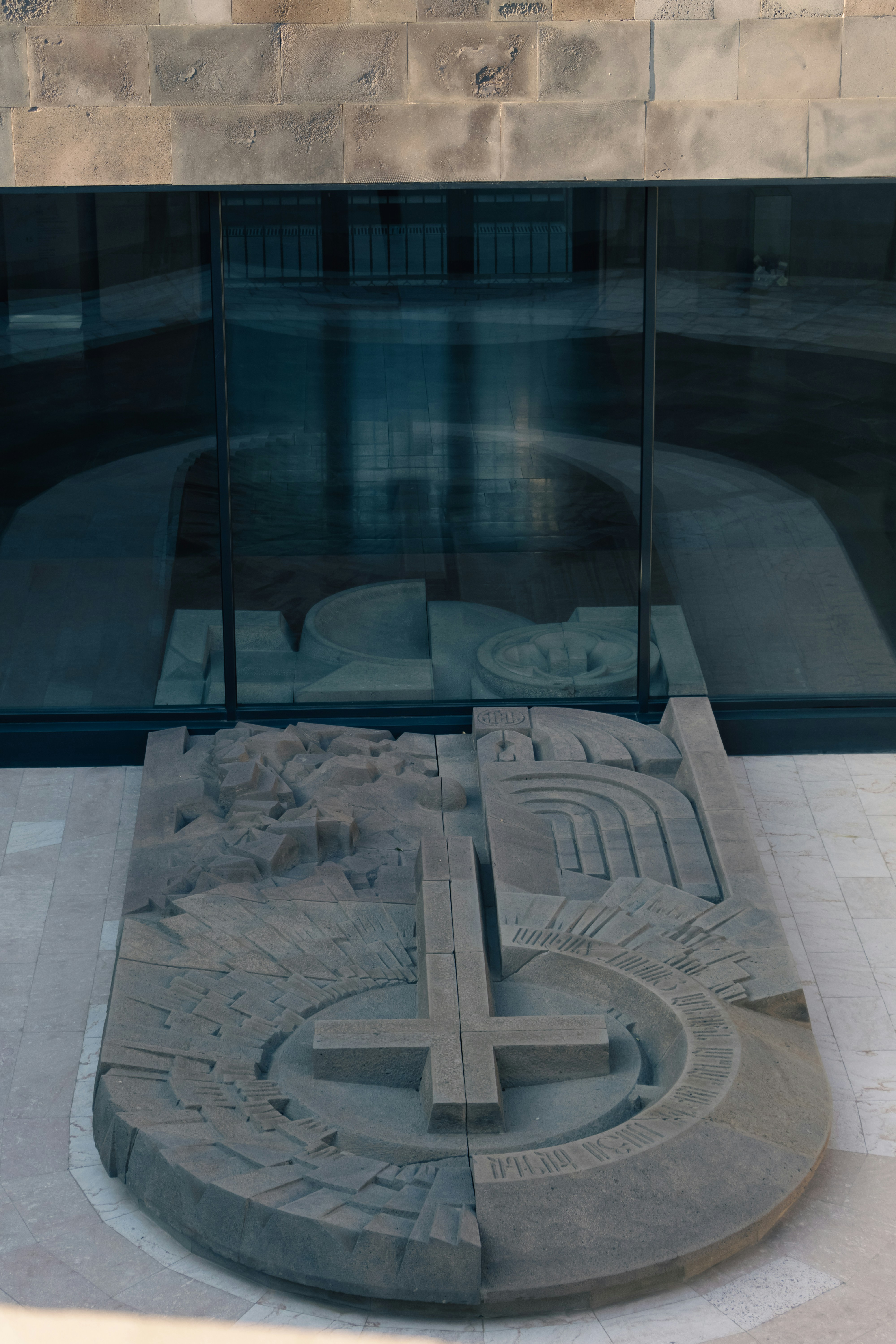 Concentric Cross in Stone Under a Modern Glass Facade