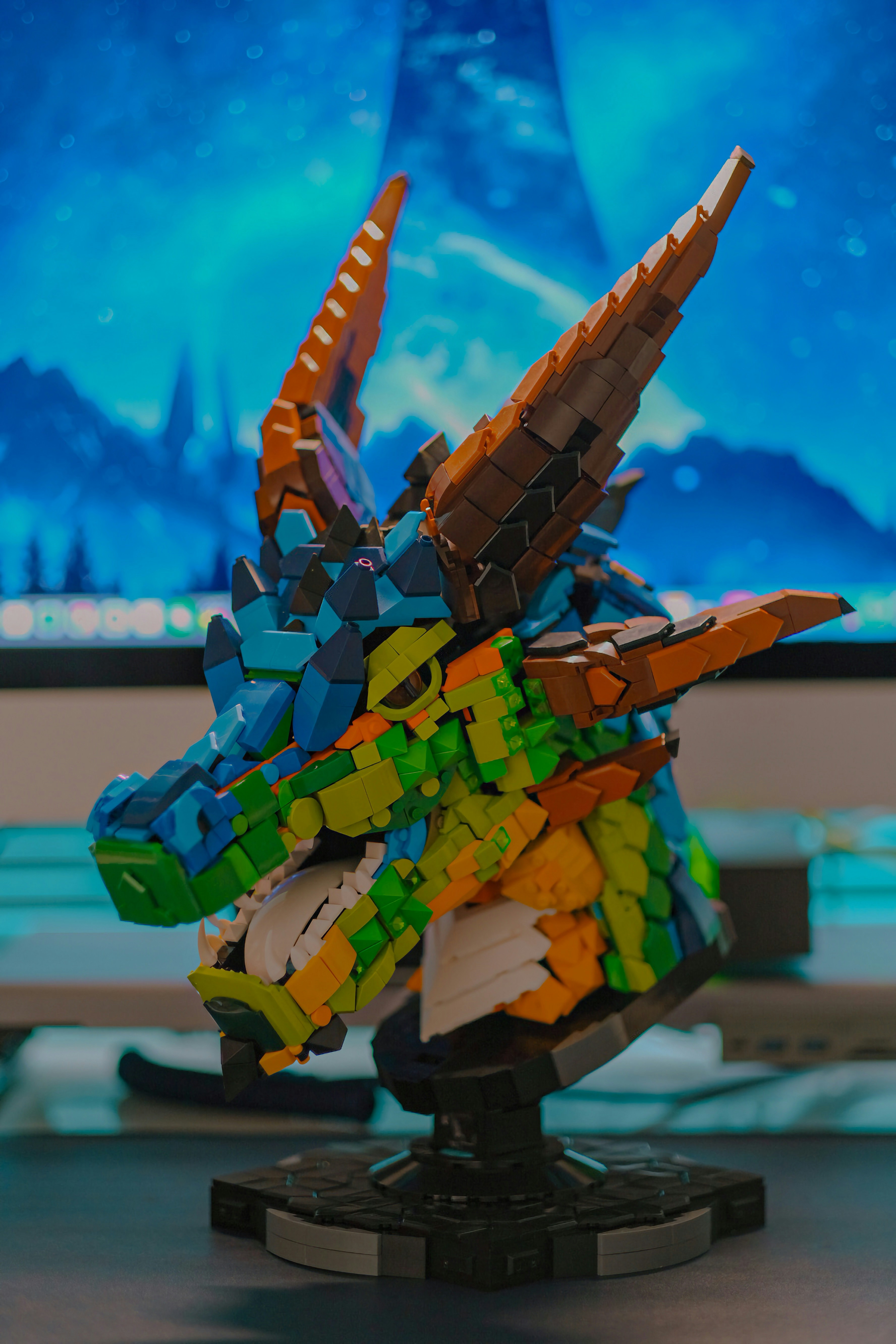 Aurora in Bricks: A Multicolor LEGO Dragon Bust on a Desk Under a Cyan Screen