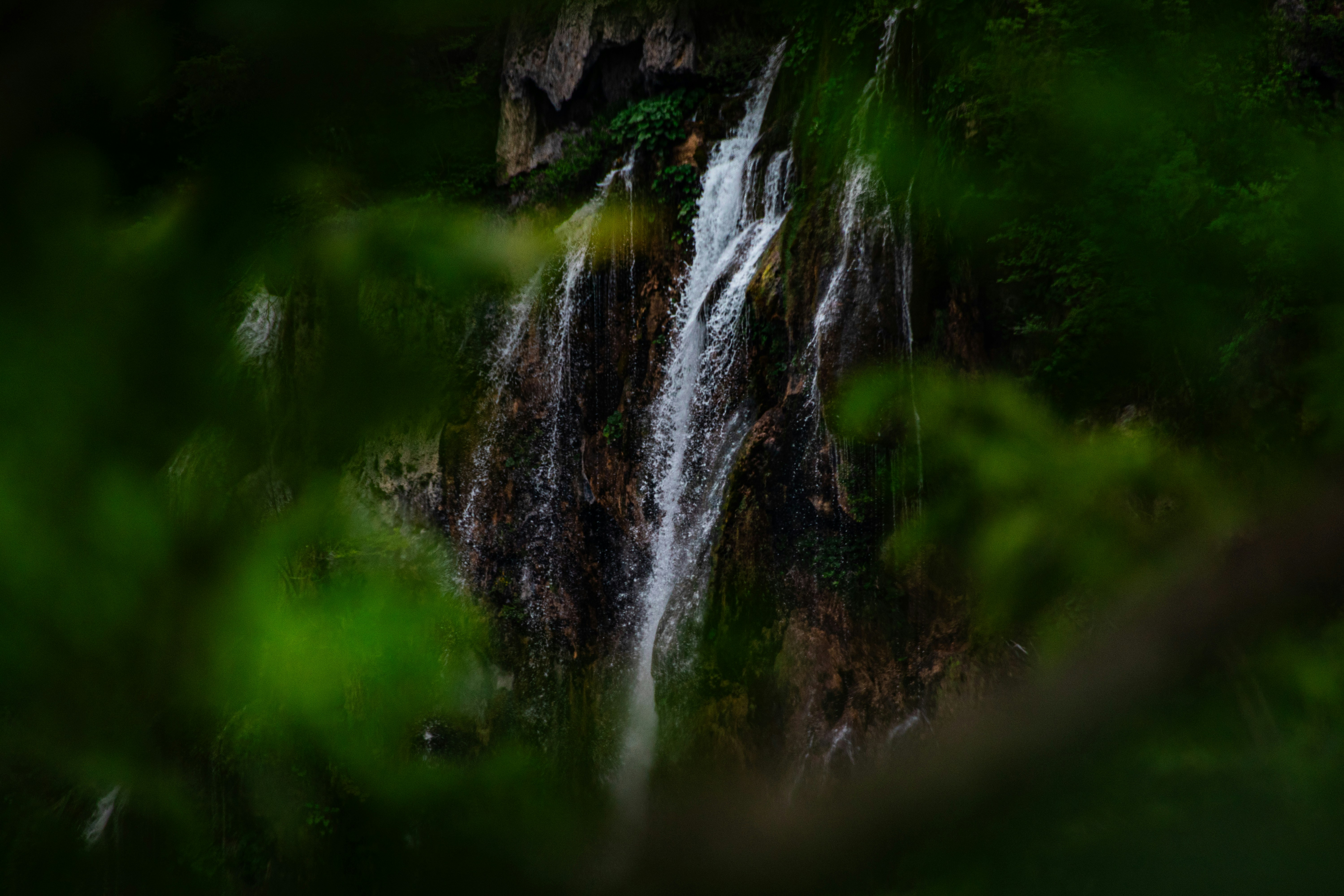 A waterfall is seen through the leaves of a tree photo – Free Croatia ...