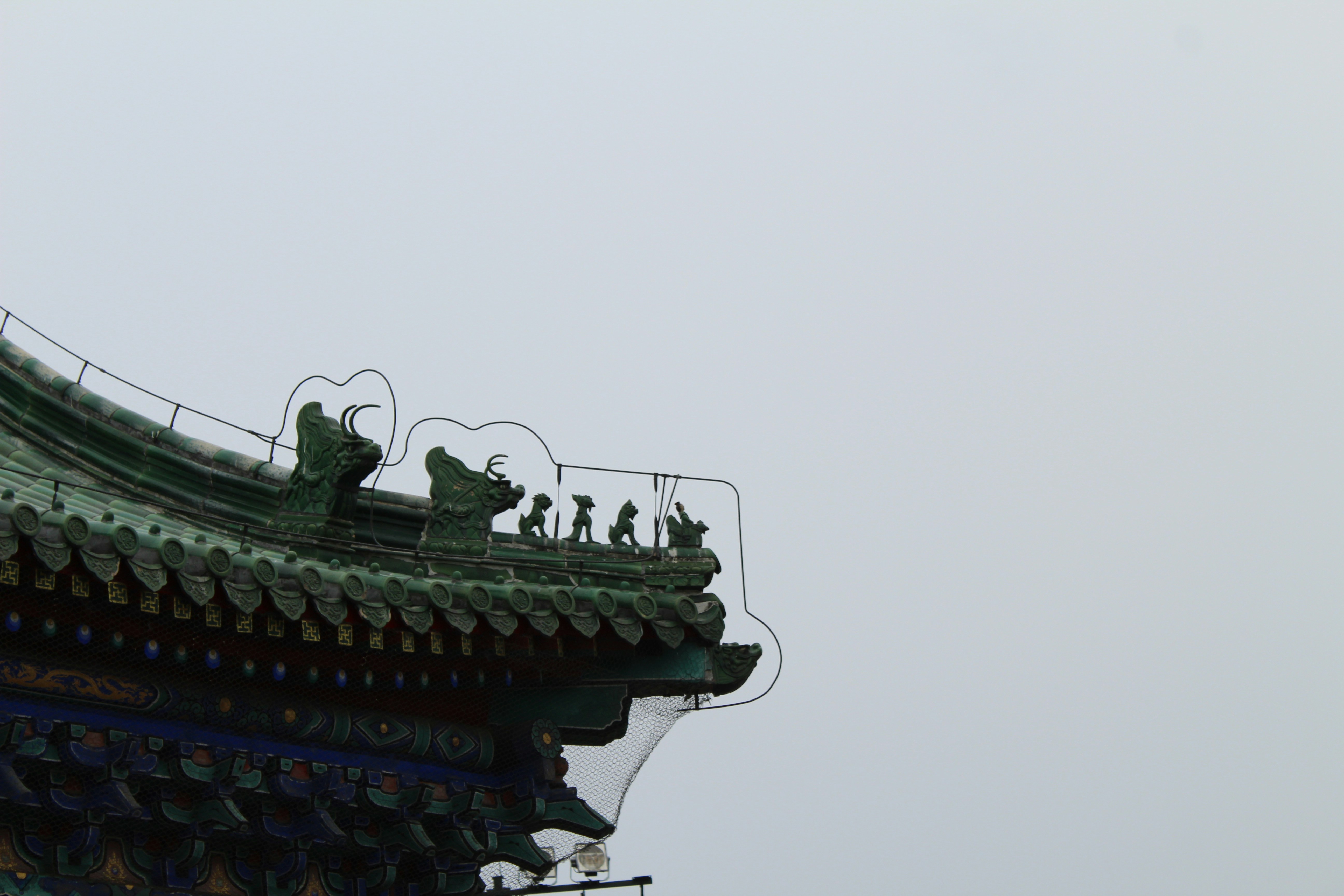 Ridge Guardians: Silhouettes of Ornate Roof Figures against a Quiet Sky