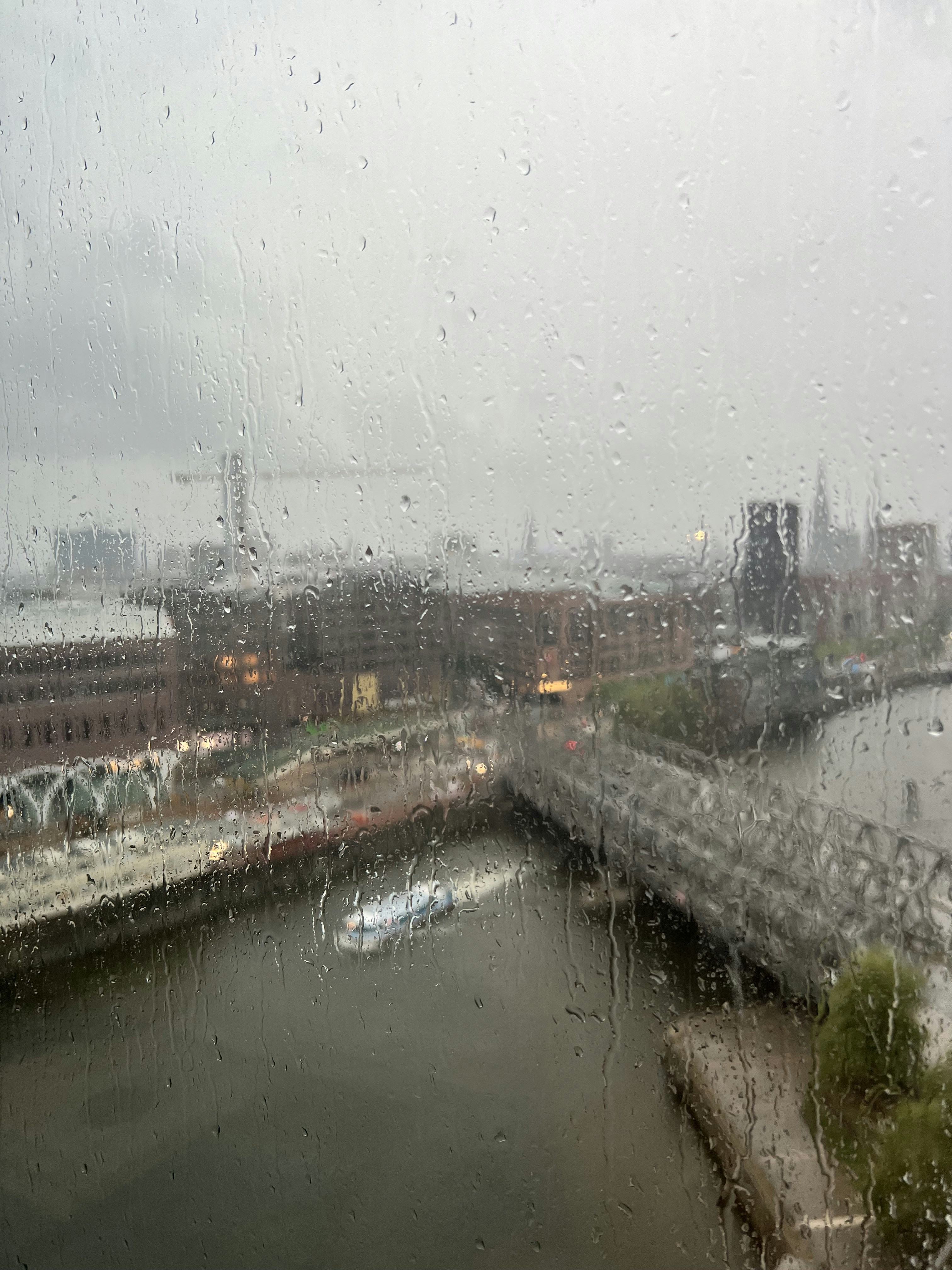 Rainy riverside cityscape through a glassy veil