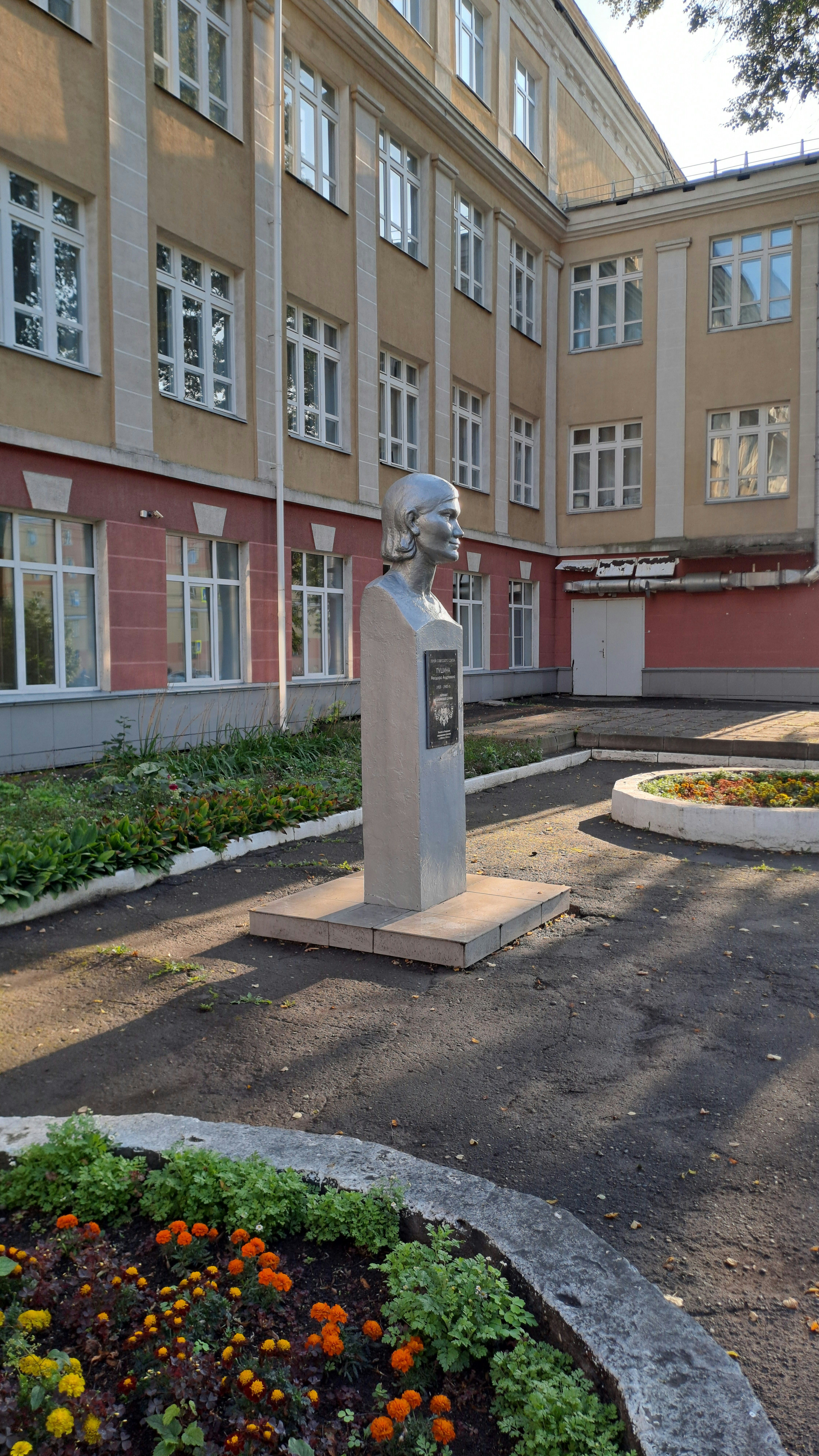 Bust in the Courtyard: A Quiet Portrait Beneath Red-Walled Windows