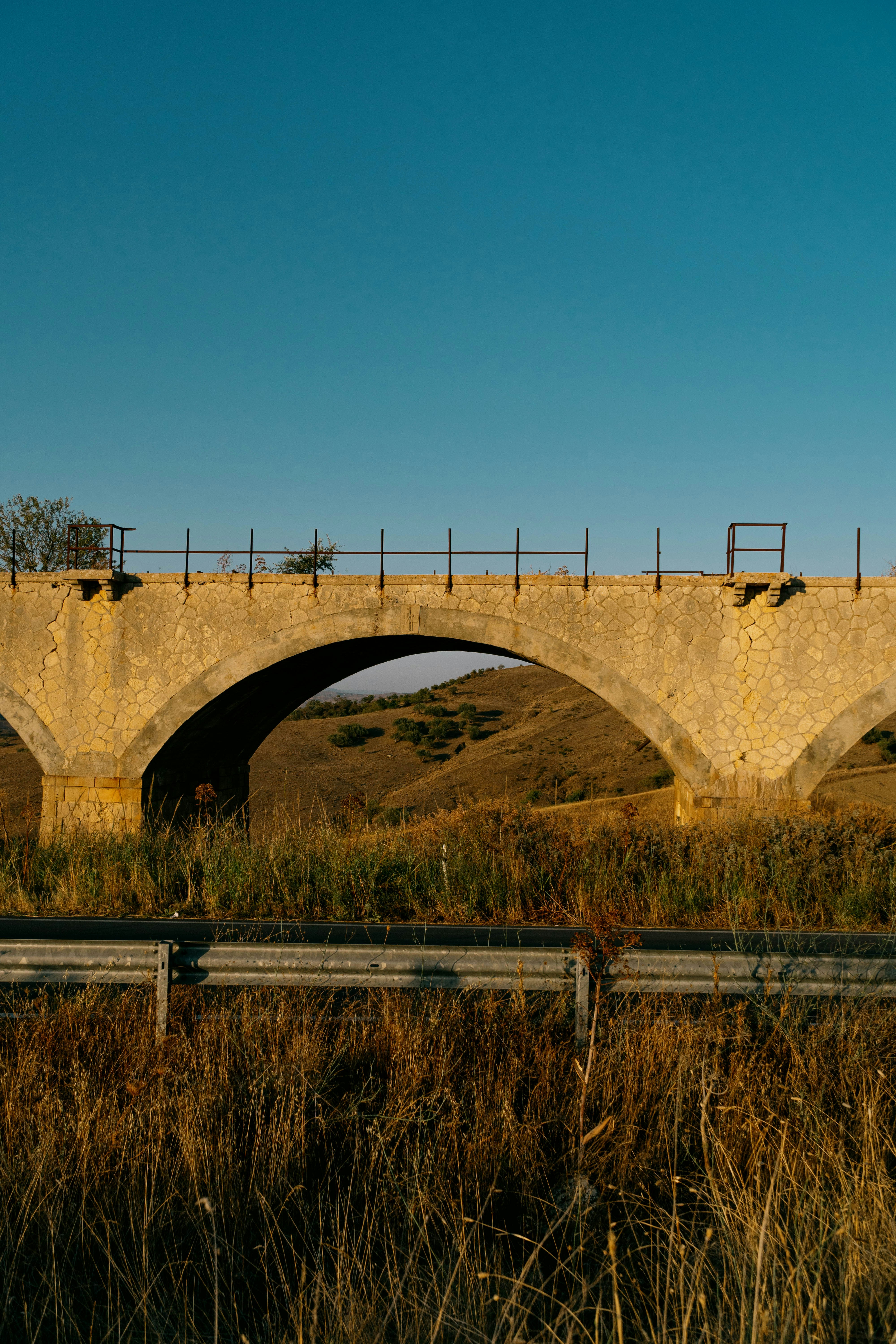 Golden Hour Arch: Sunlit Stone Bridge Framing a Quiet Field