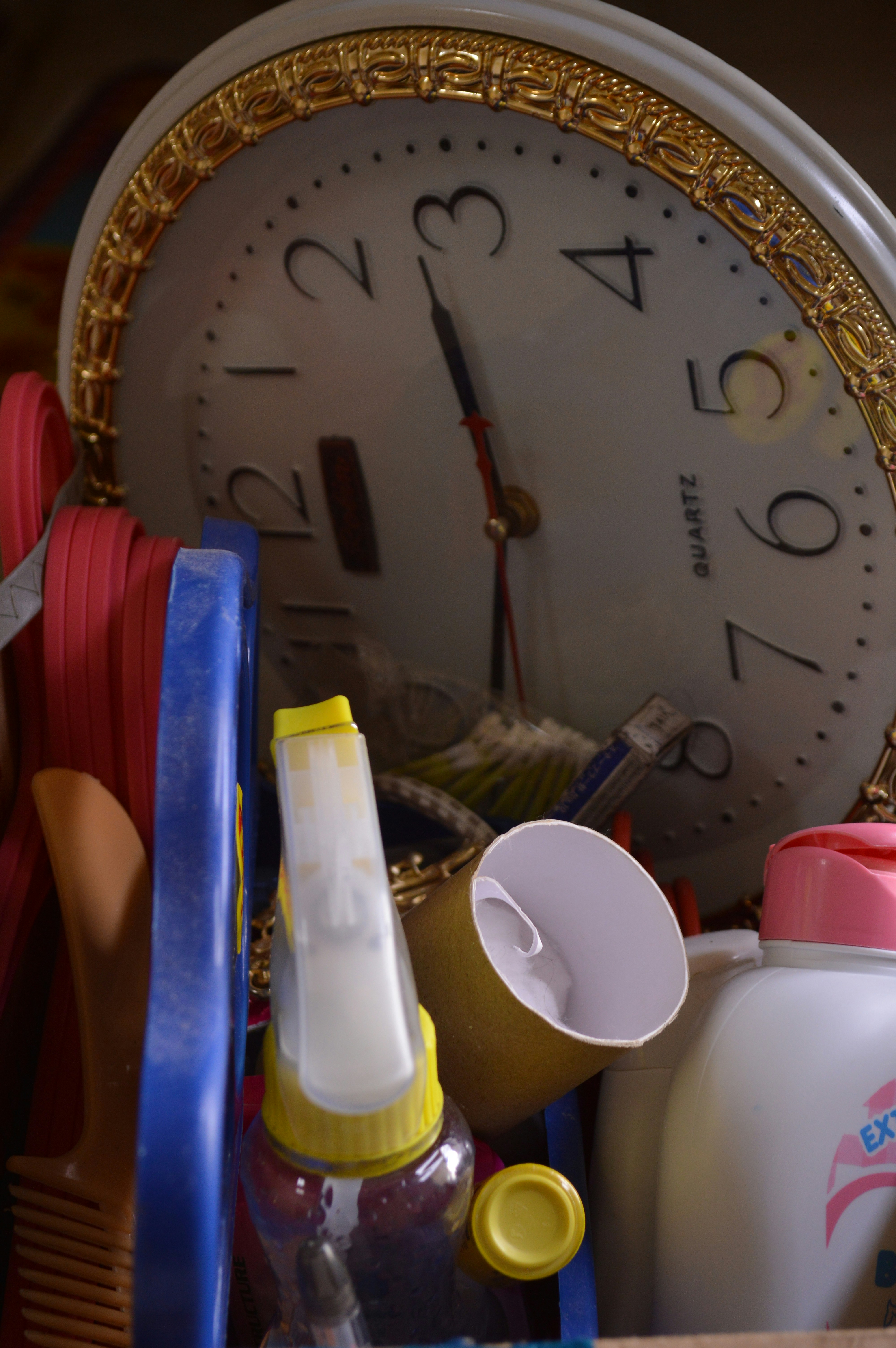 a cluttered scene with various objects in disarray | A close up of a clock surrounded by other items