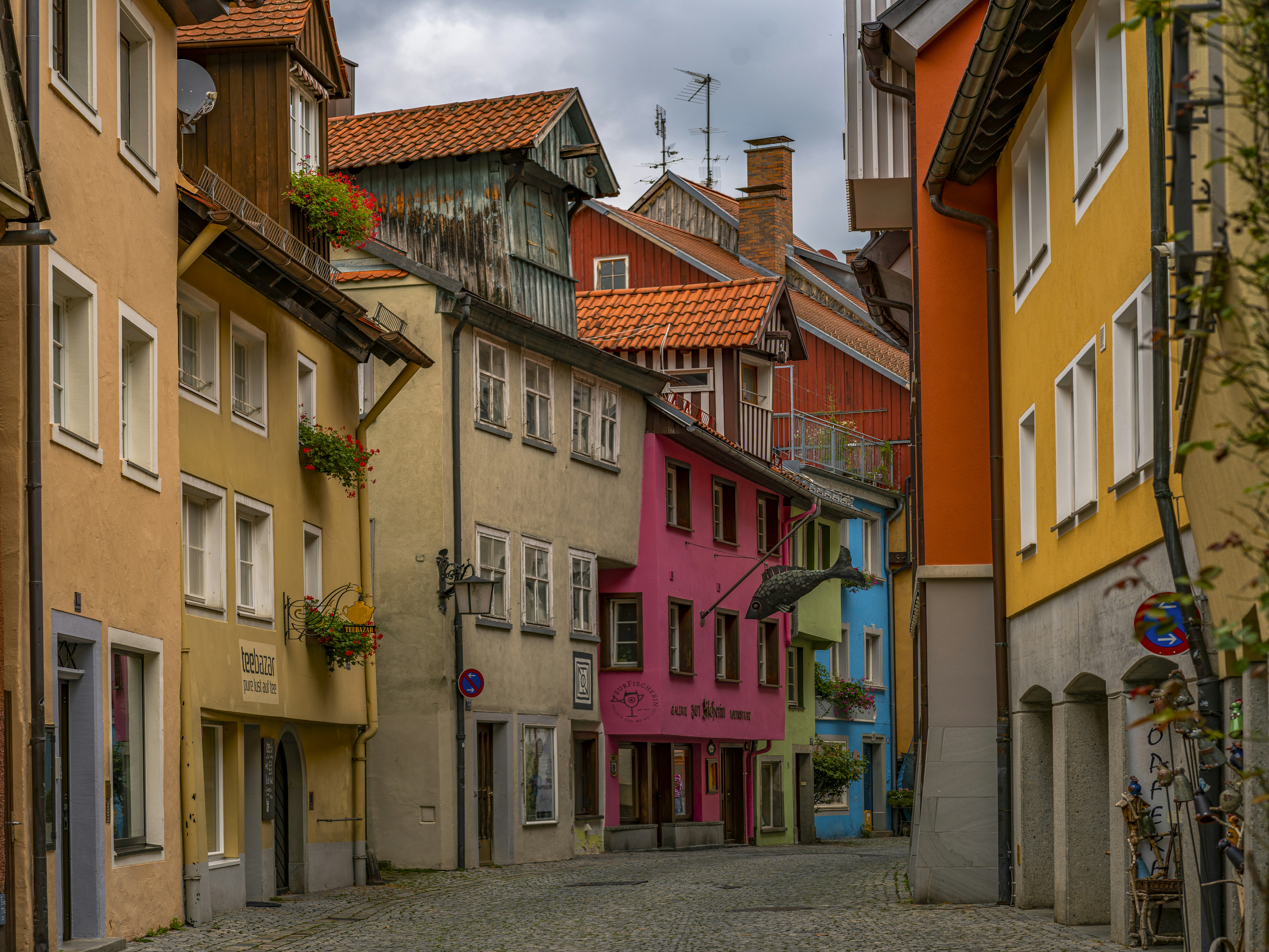 Colorful buildings line a narrow cobblestone street under an overcast sky.