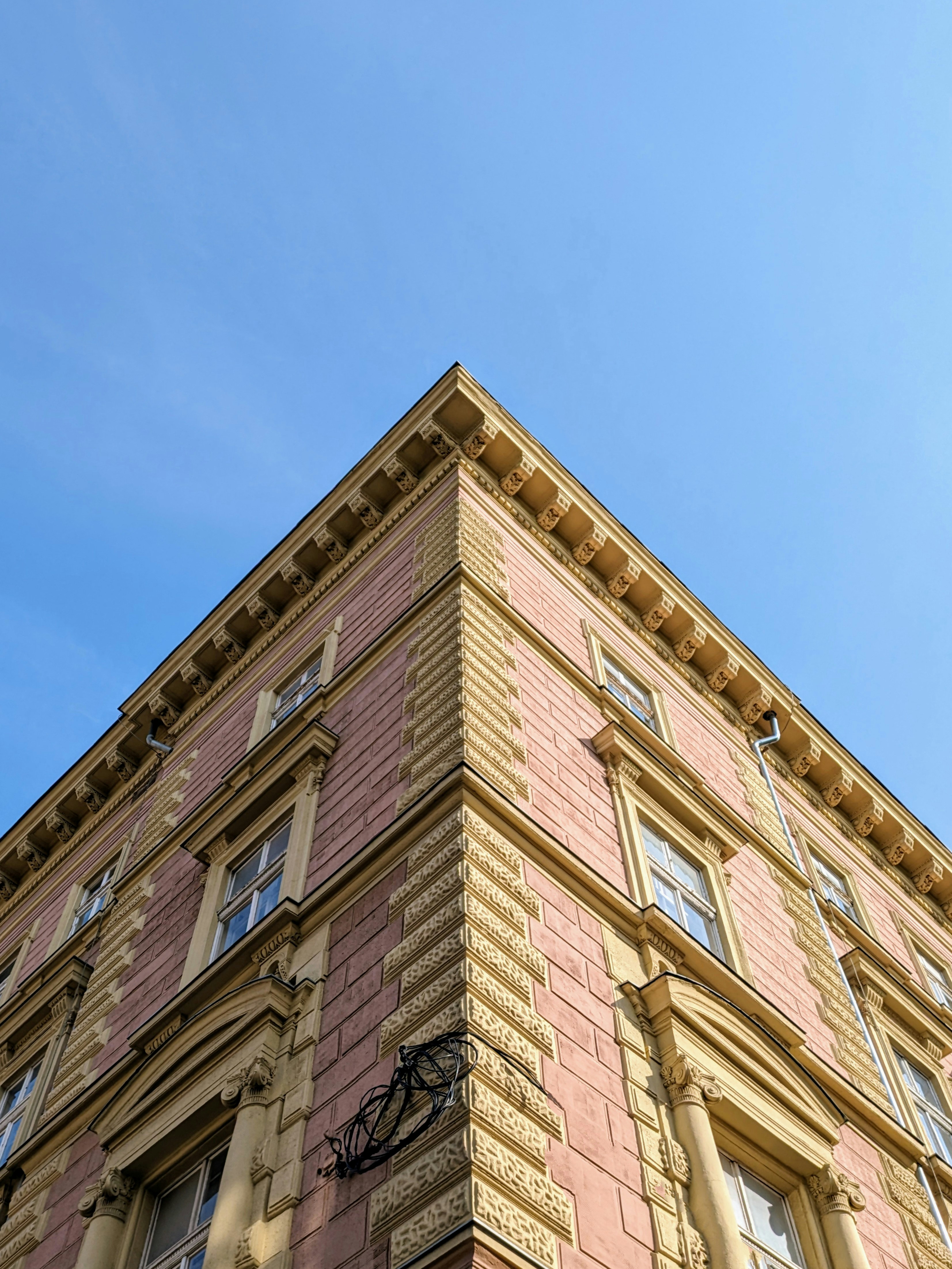 Historic building corner showcasing intricate stonework and vibrant colors against a clear blue sky.