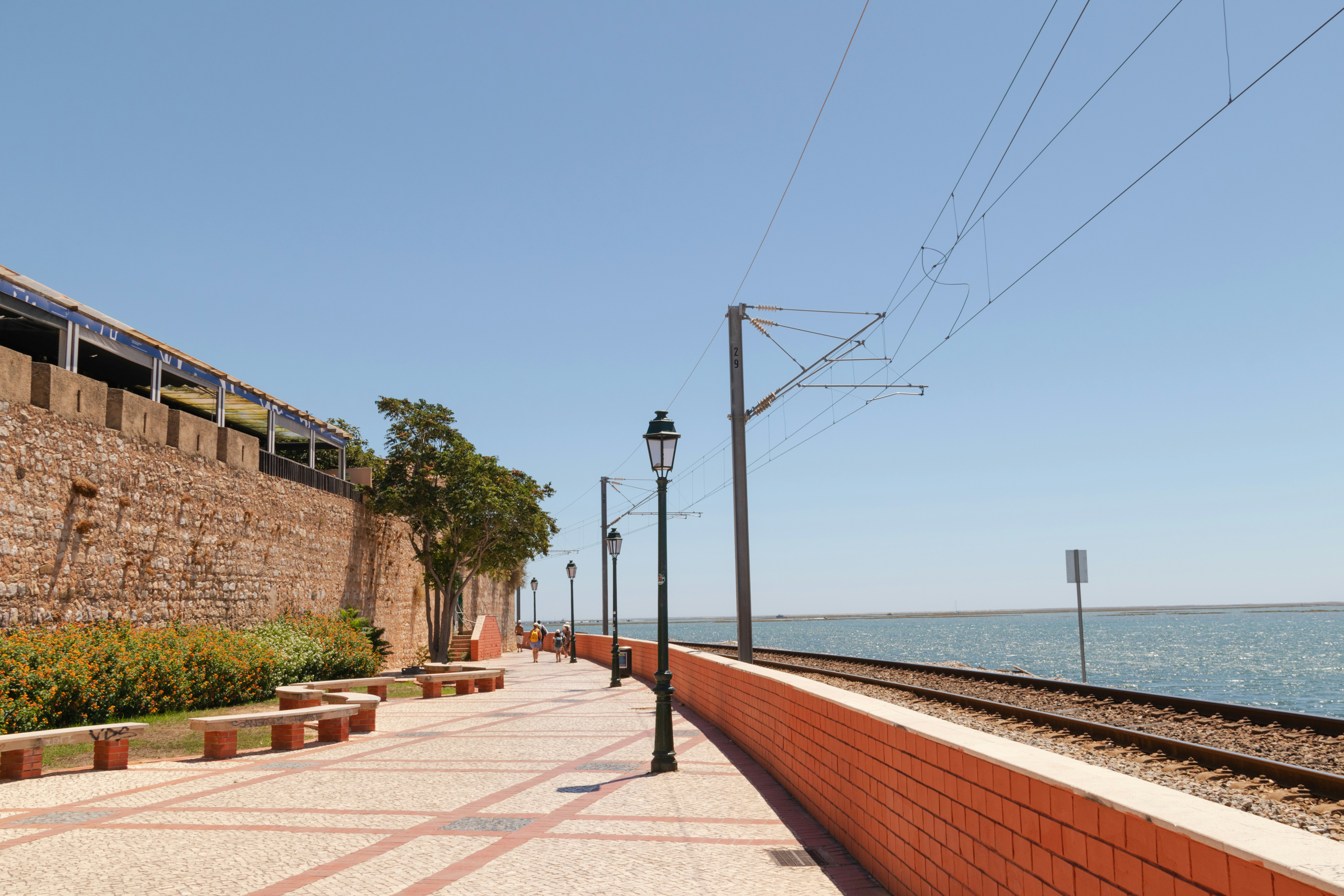 A train traveling down tracks next to a body of water photo – Free ...