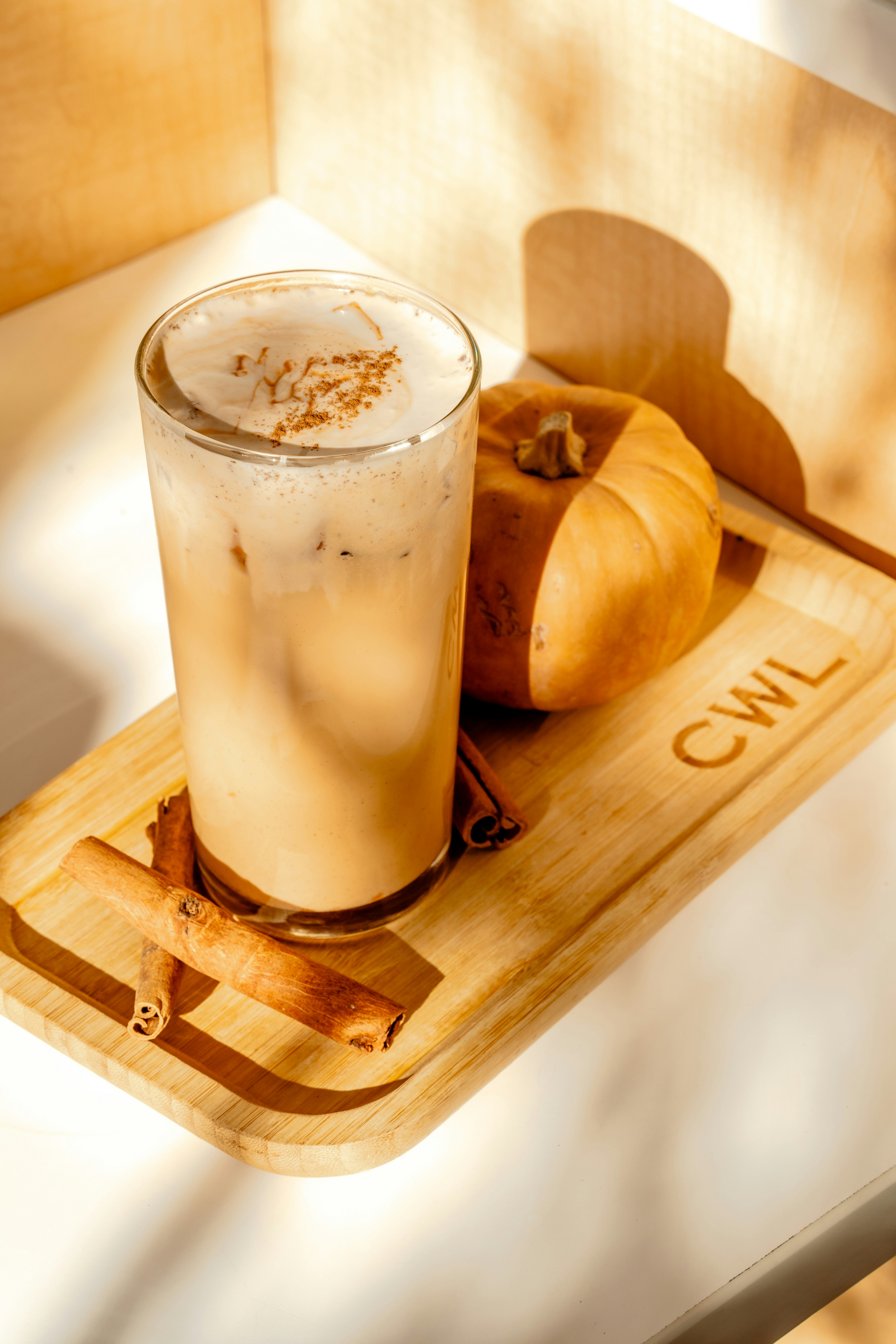 Creamy Autumn Moment: A Glass of Iced Coffee on a Pumpkin-Studded Board