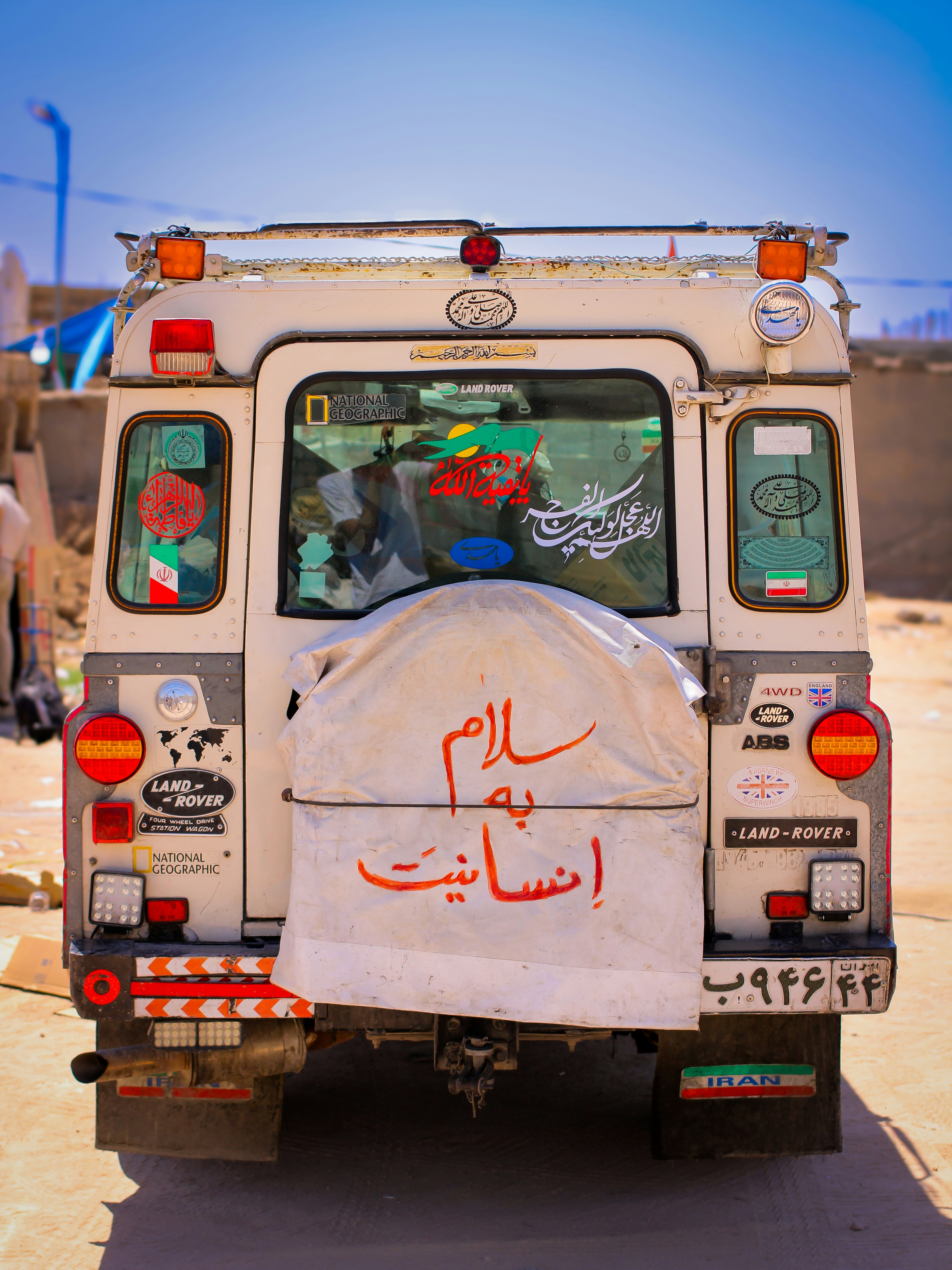 Stickered Desert Rover: Rear View of a Tale-Worn Land Rover