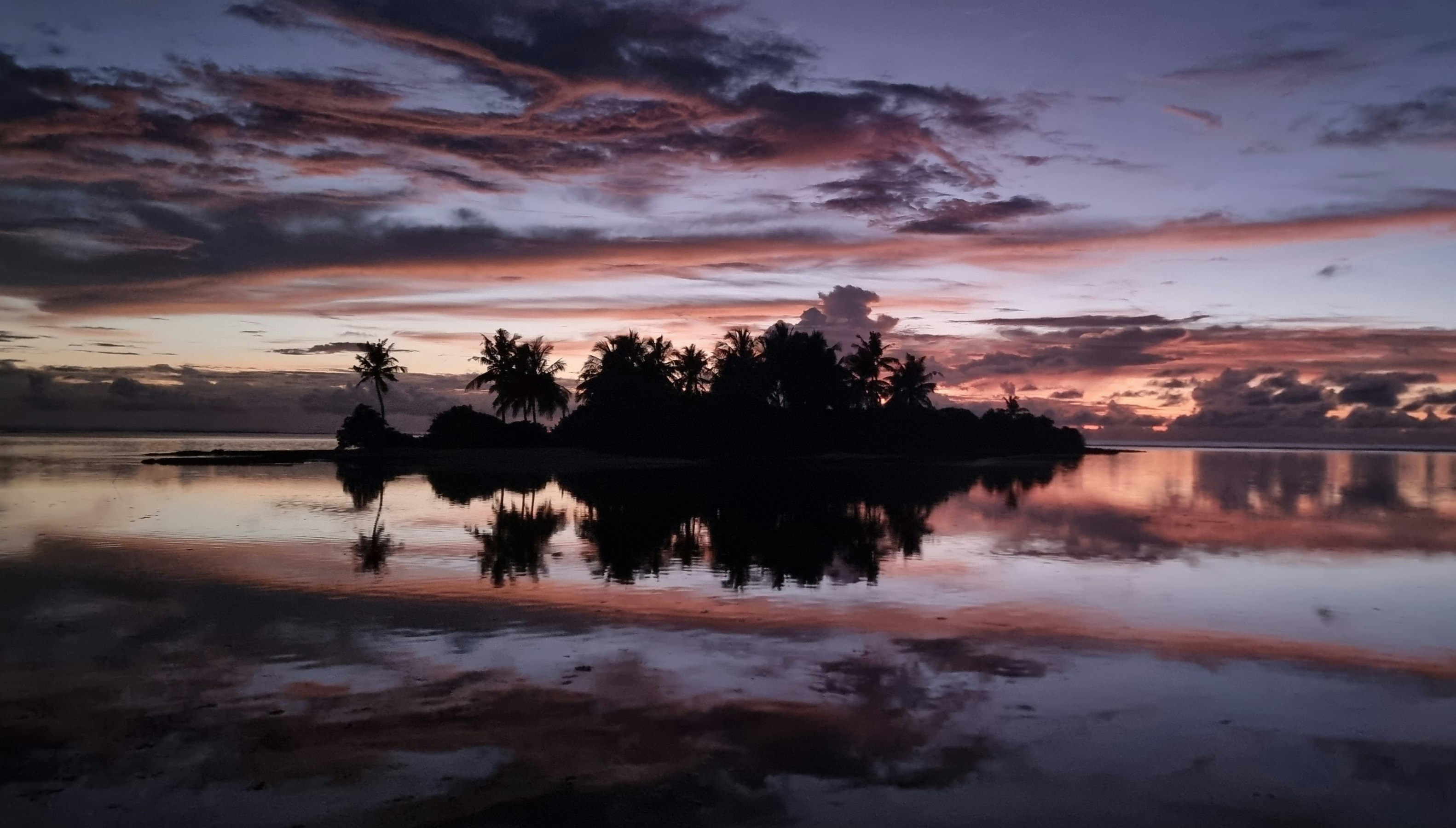 Dusk Reflections: Silhouetted Palms Across a Glassy Lagoon