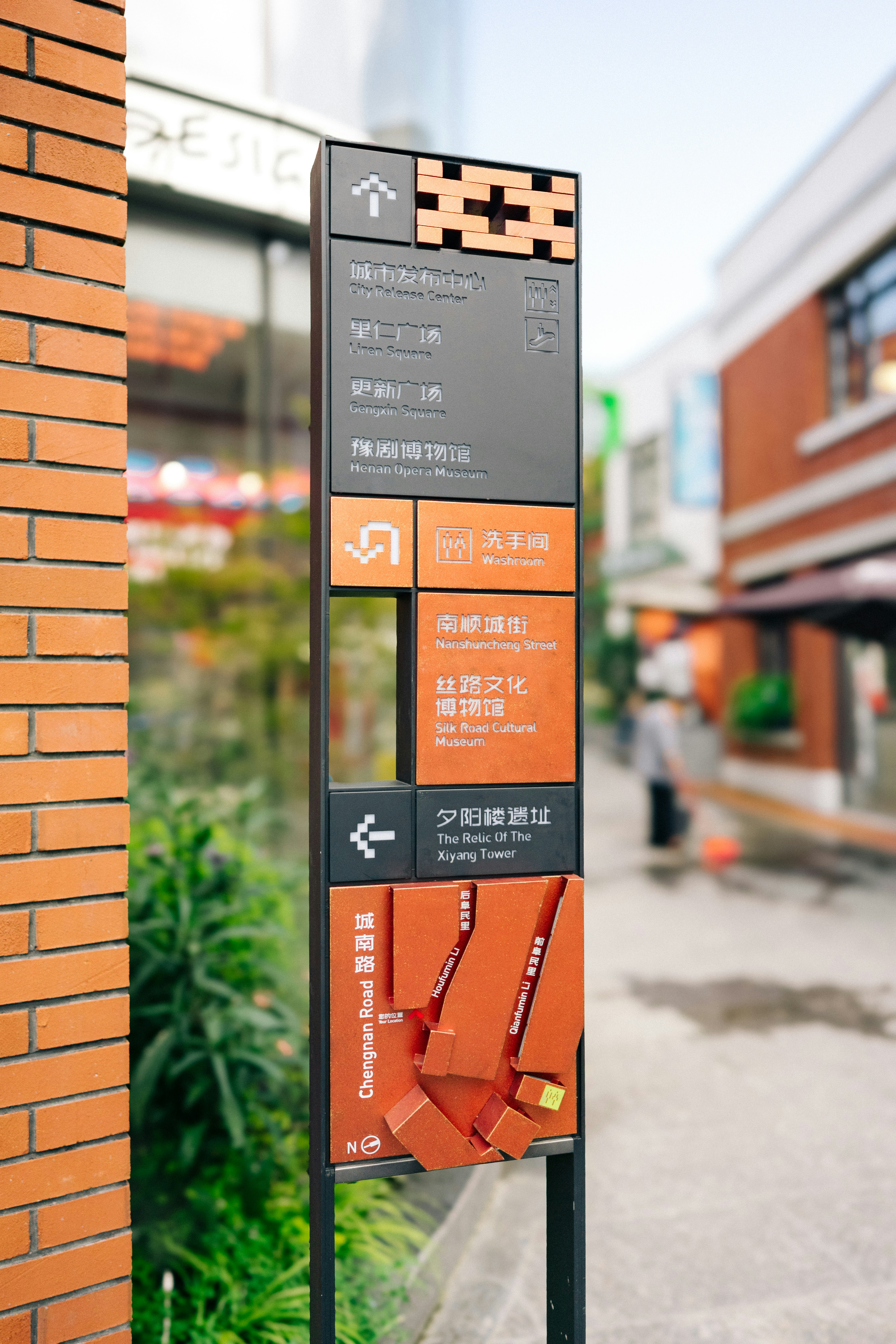 Tall orange signpost guiding visitors through a pedestrian street