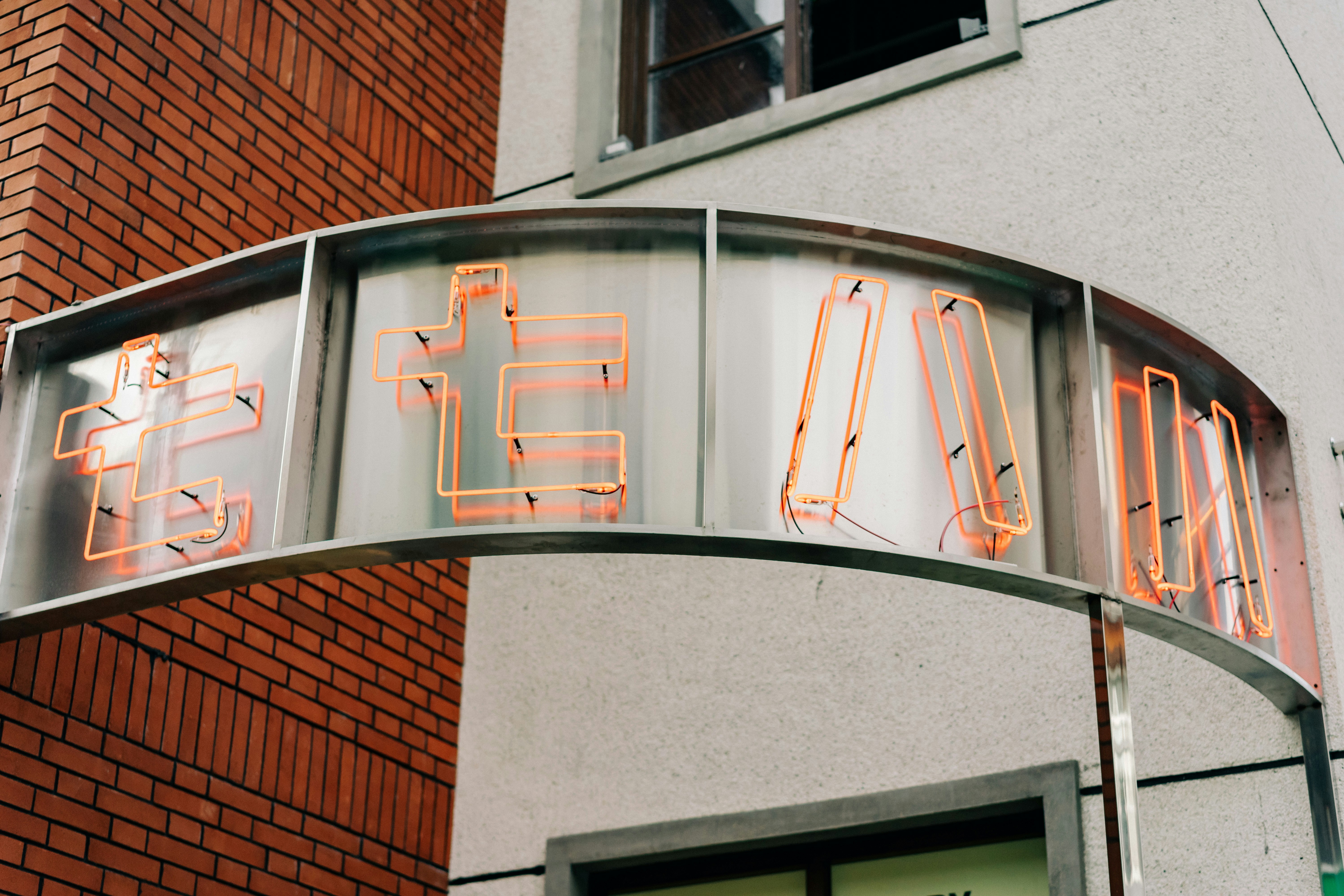 Neon Arc Across an Urban Facade: Warm Tubes Curving Over Brick and Plaster