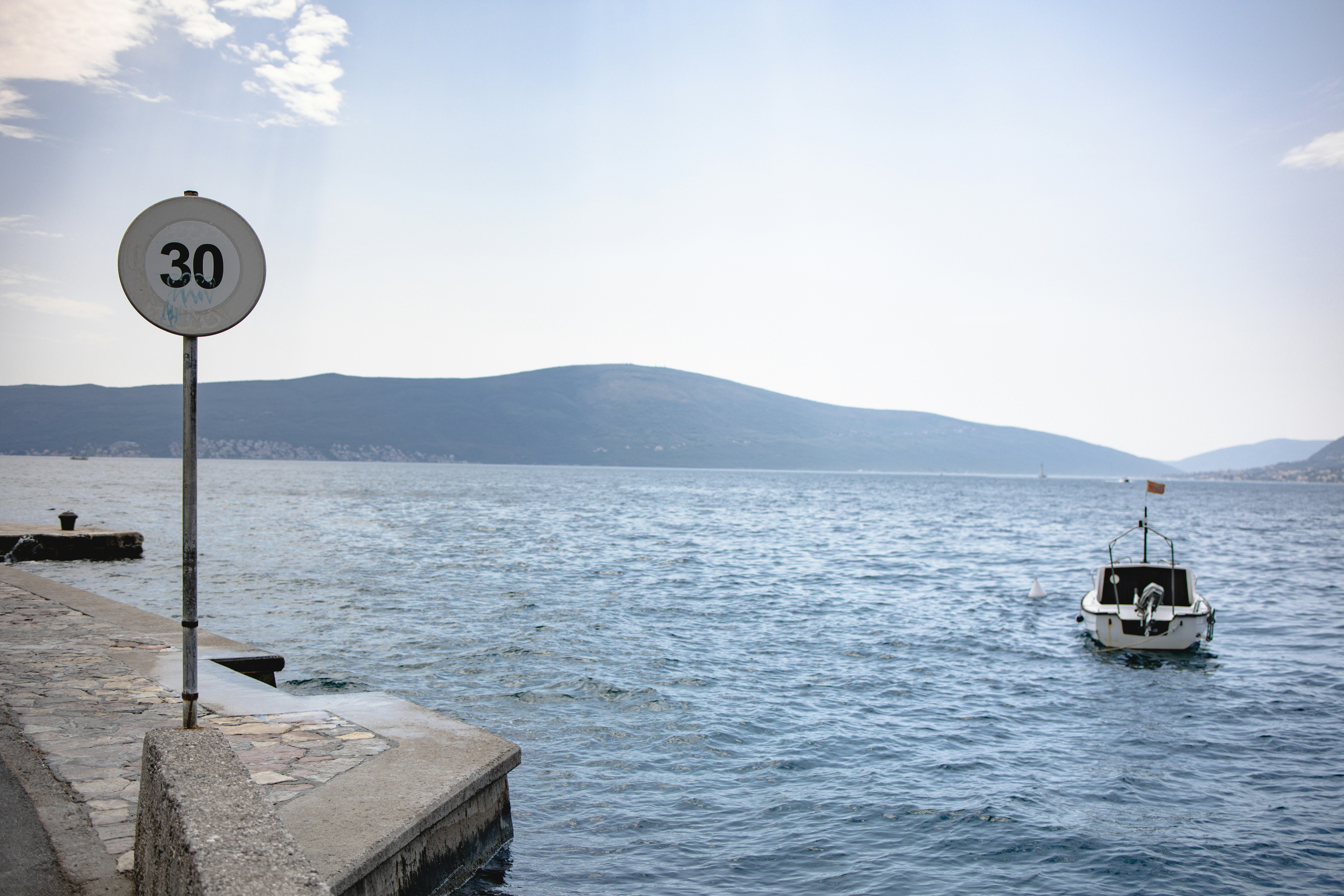 Harbor Threshold: A Quiet Pier Sign Framing a Distant Boat