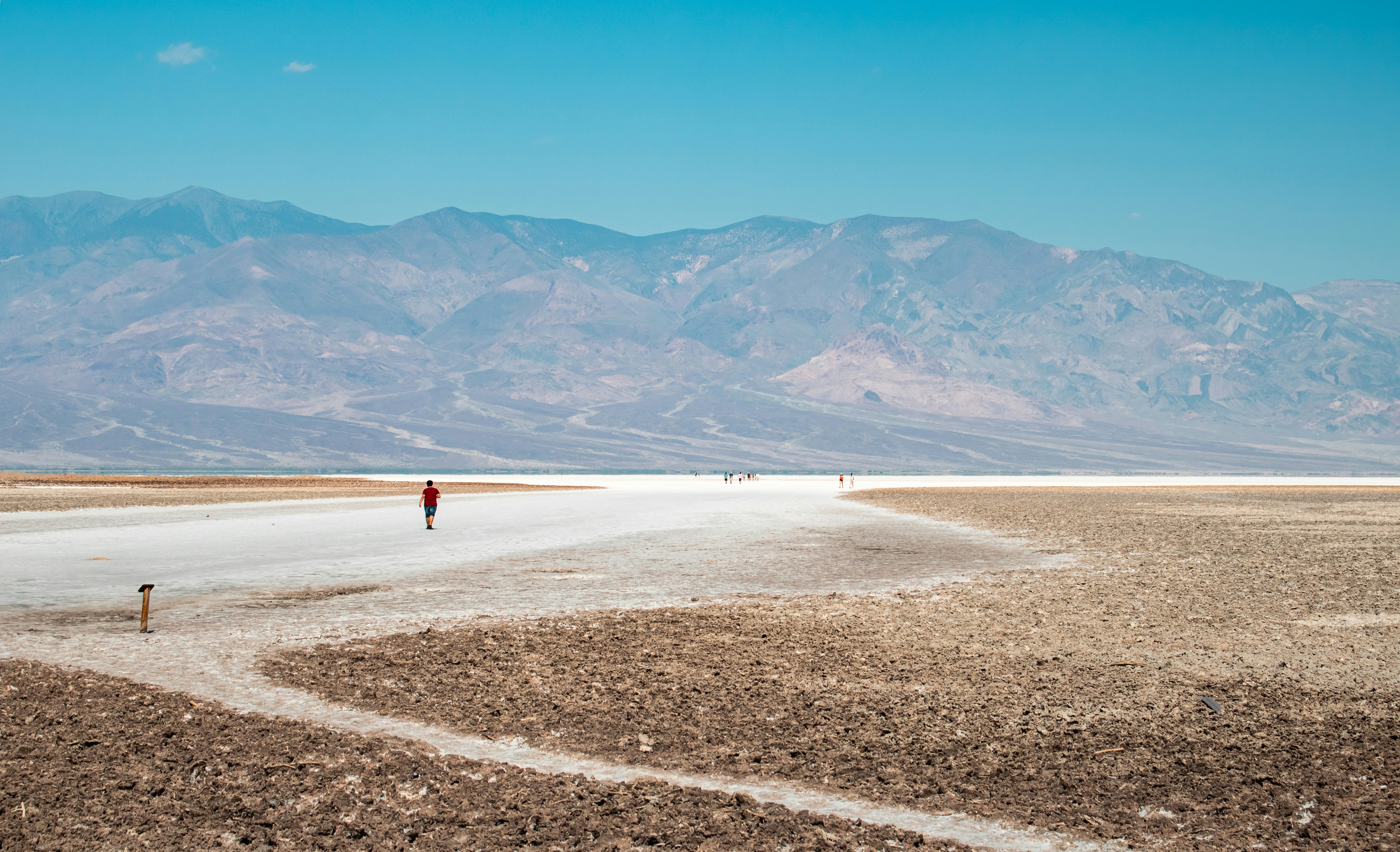 A person walking across a desert plain with mountains in the background ...
