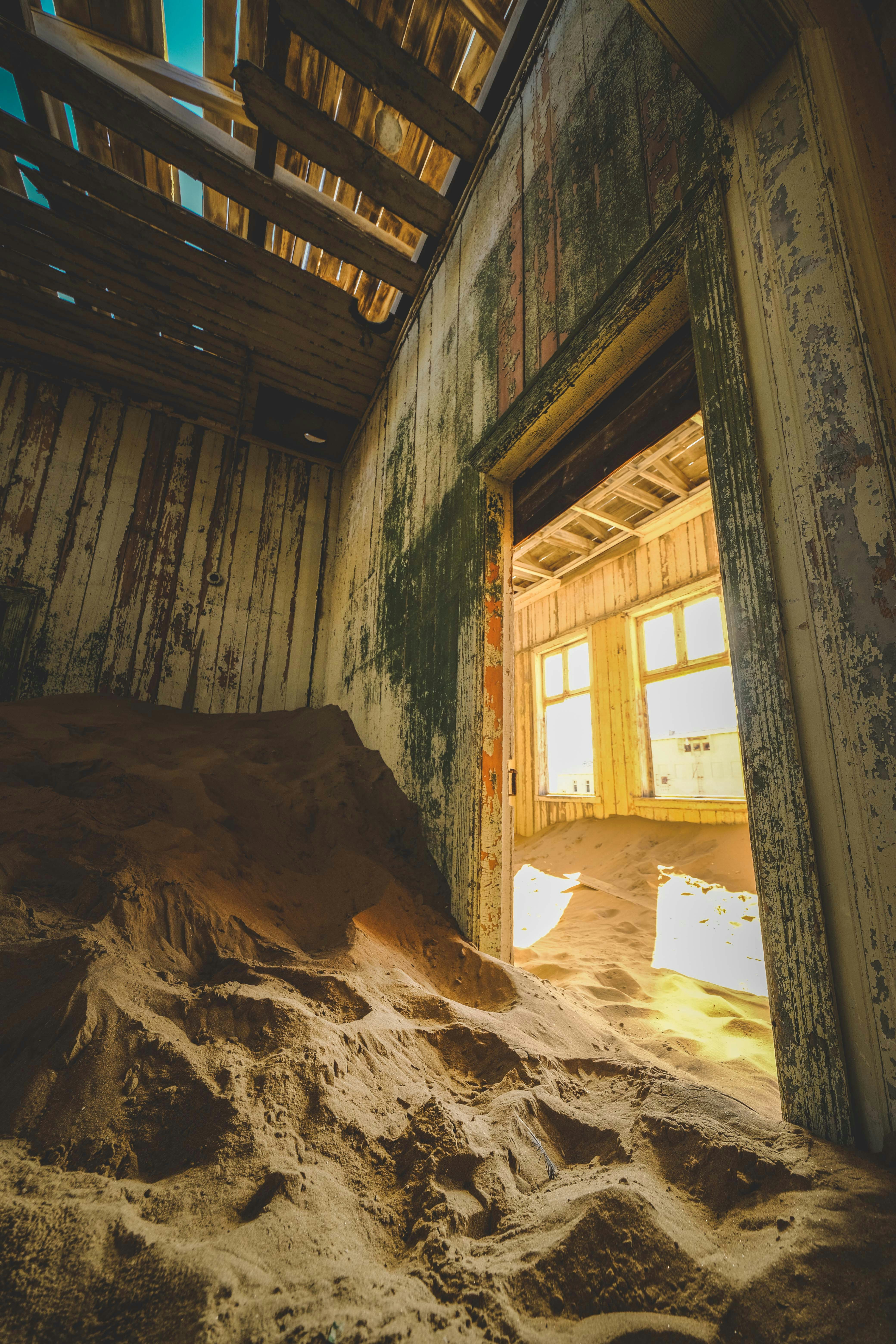 Threshold of Light: Sand-Dusted Interior Through a Weathered Doorway