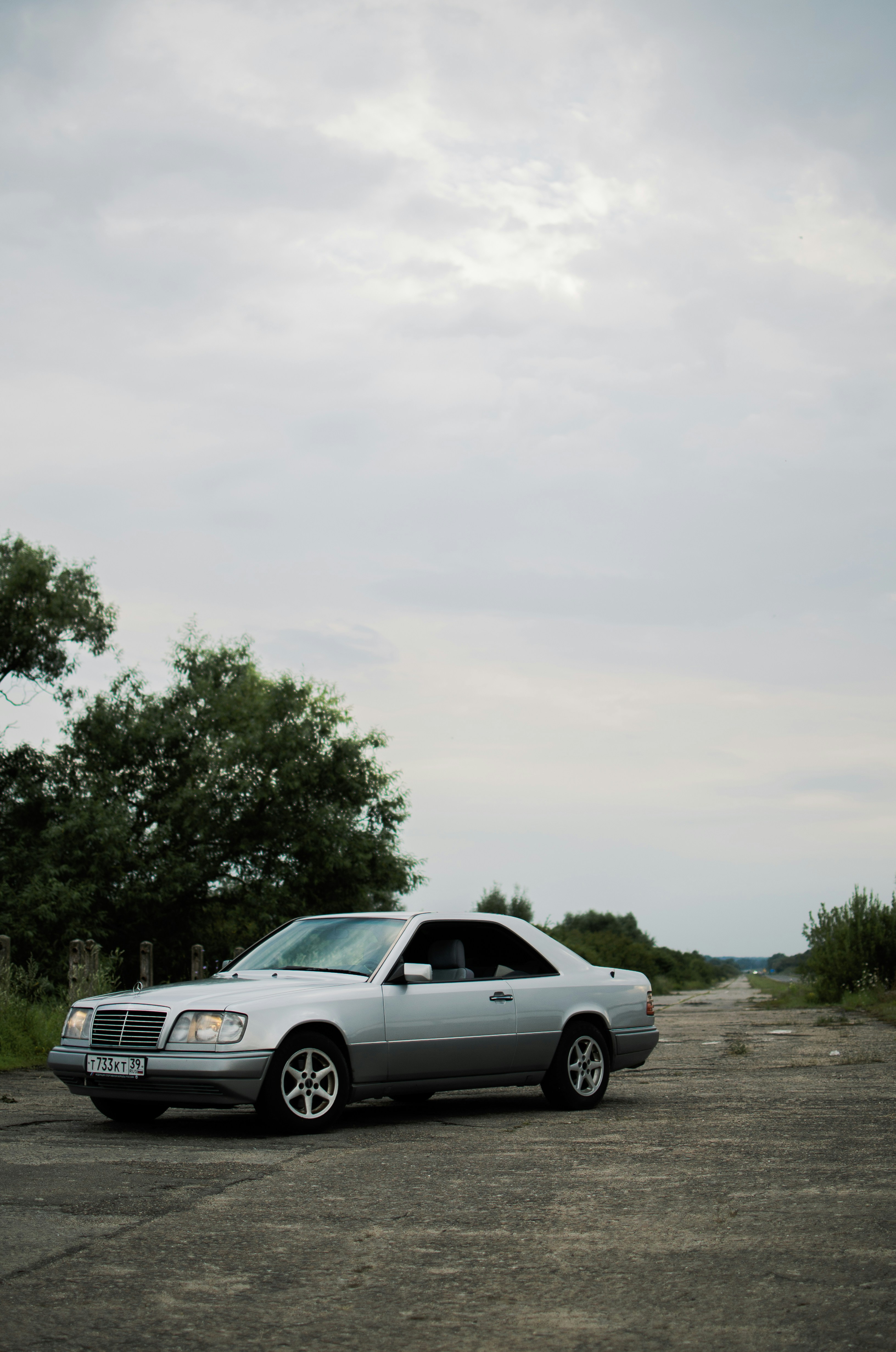 Silver Mercedes on a Weathered Backroad Under Overcast Skies