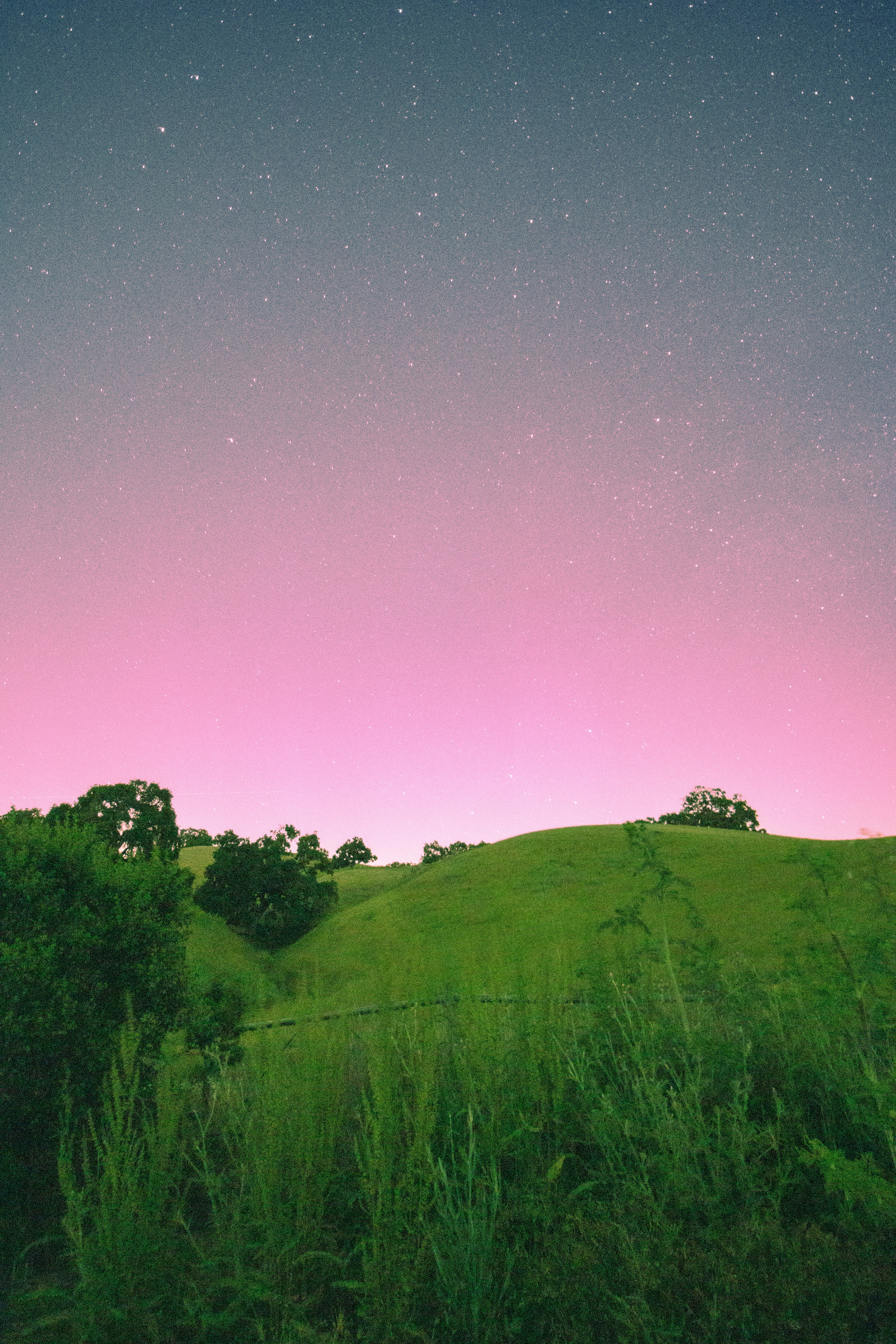 Pink Horizon Over Rolling Hills Beneath a Starry Night