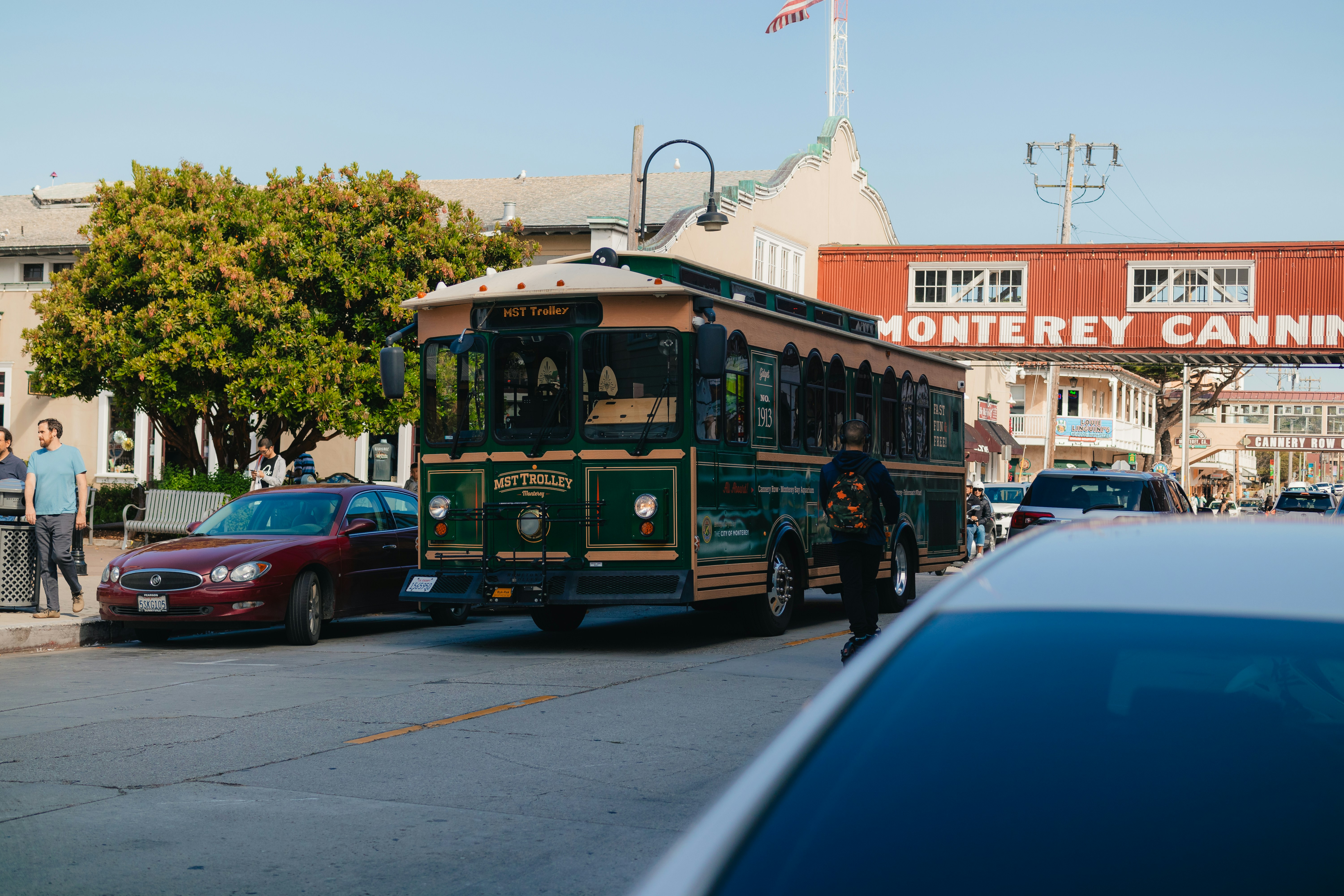 A trolley car driving down a street next to a parking lot photo – Free ...