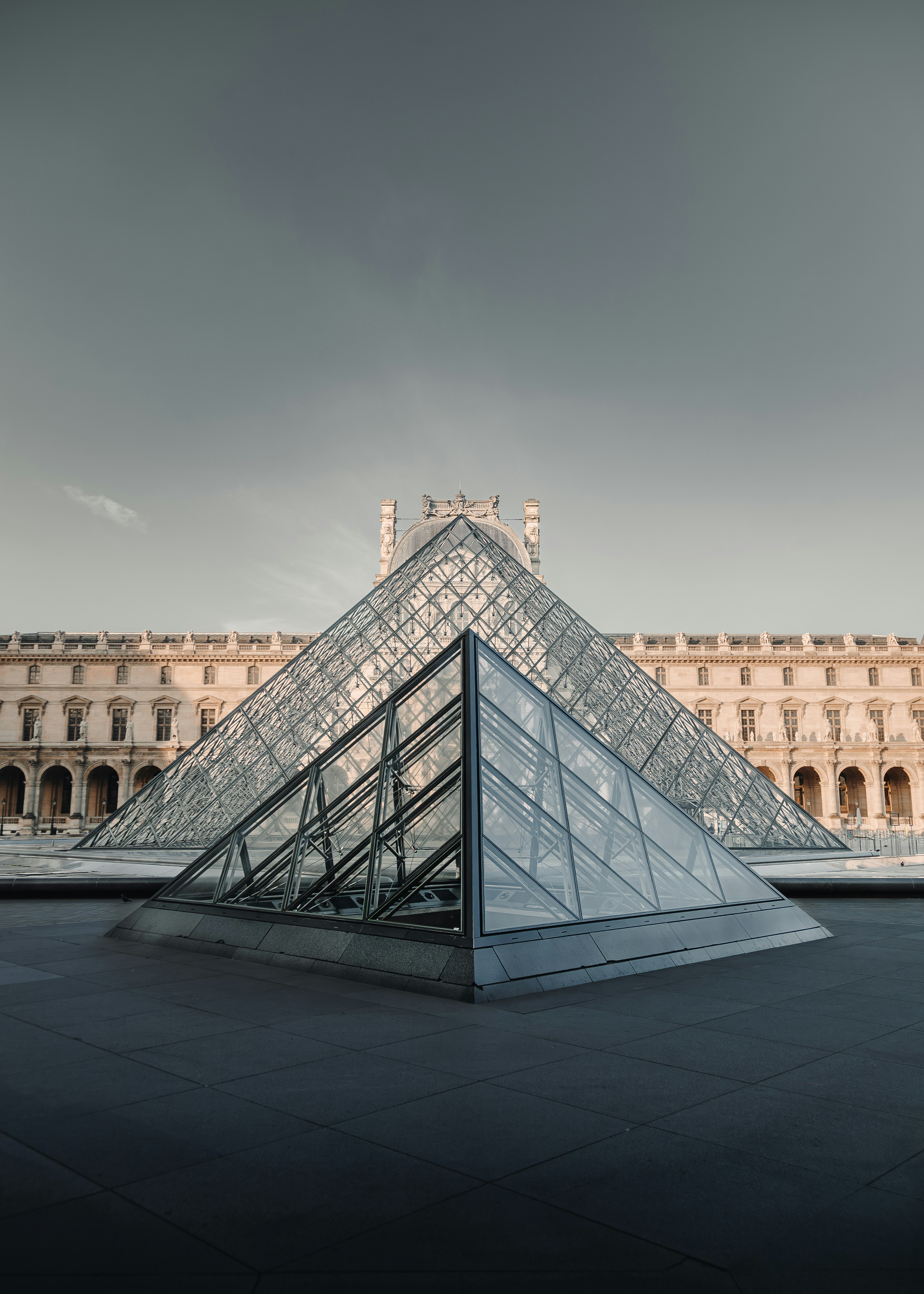 A large building with a glass pyramid in front of it photo – Free ...