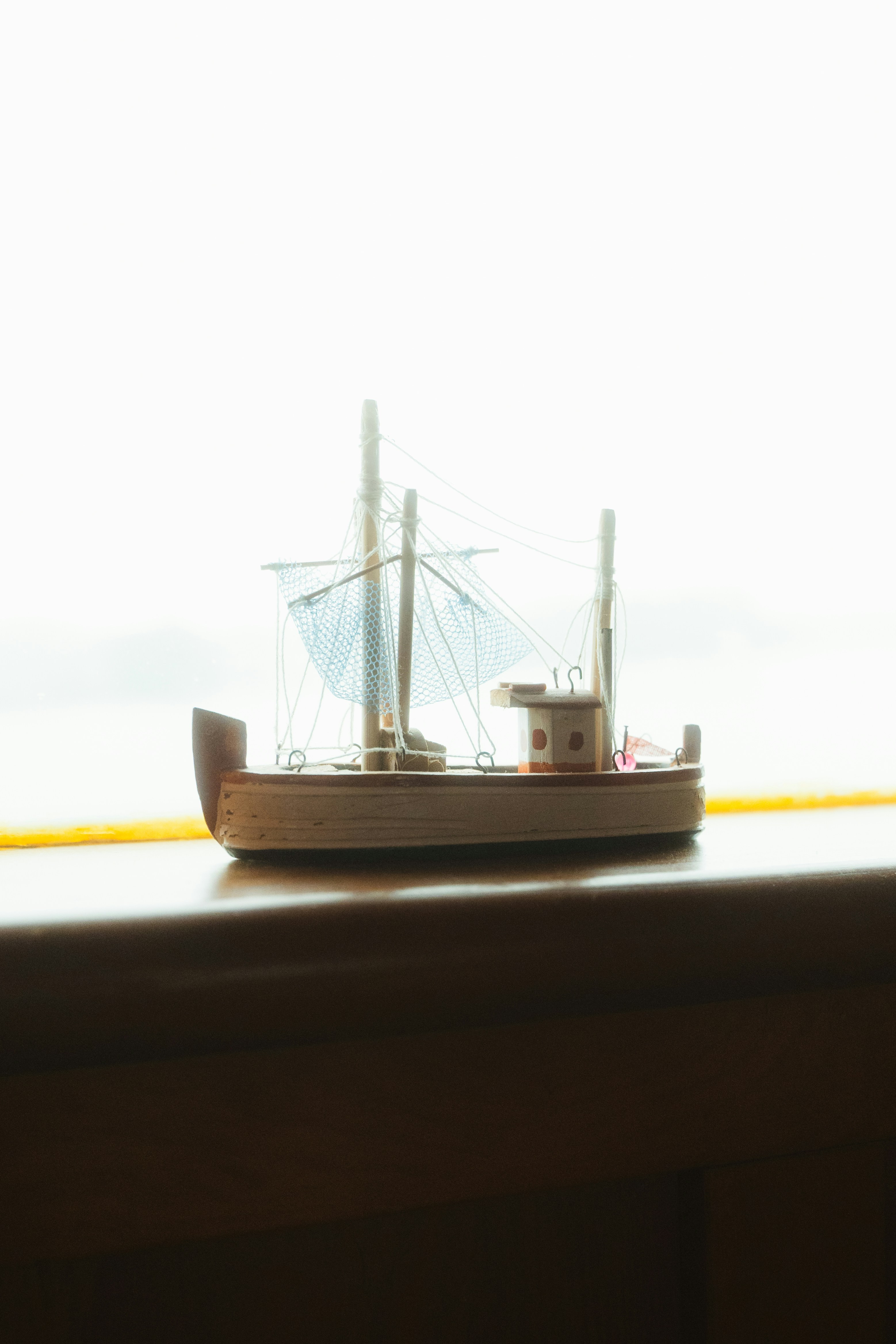 Backlit Miniature Sailboat on a Quiet Windowsill