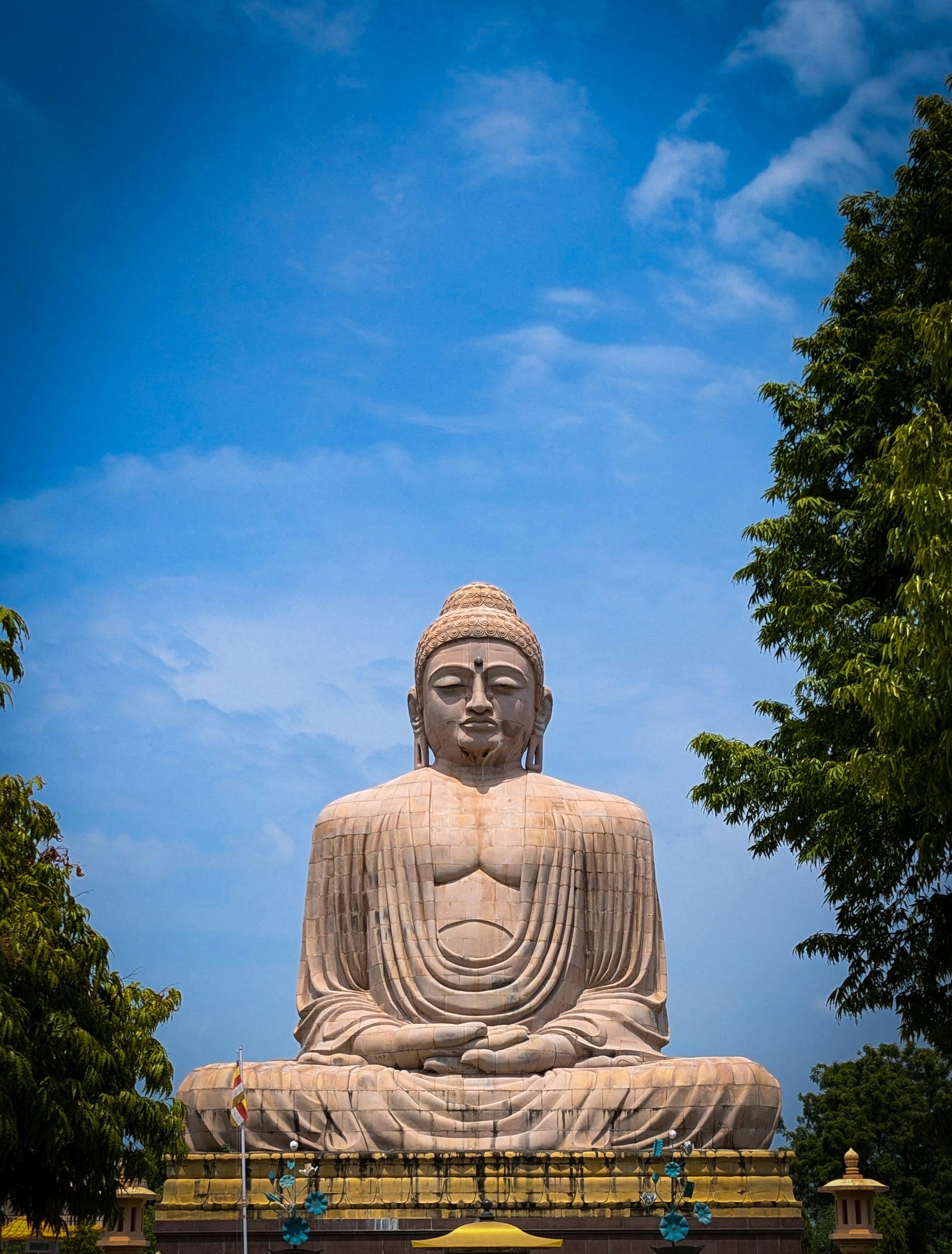 A large buddha statue sitting in the middle of a park