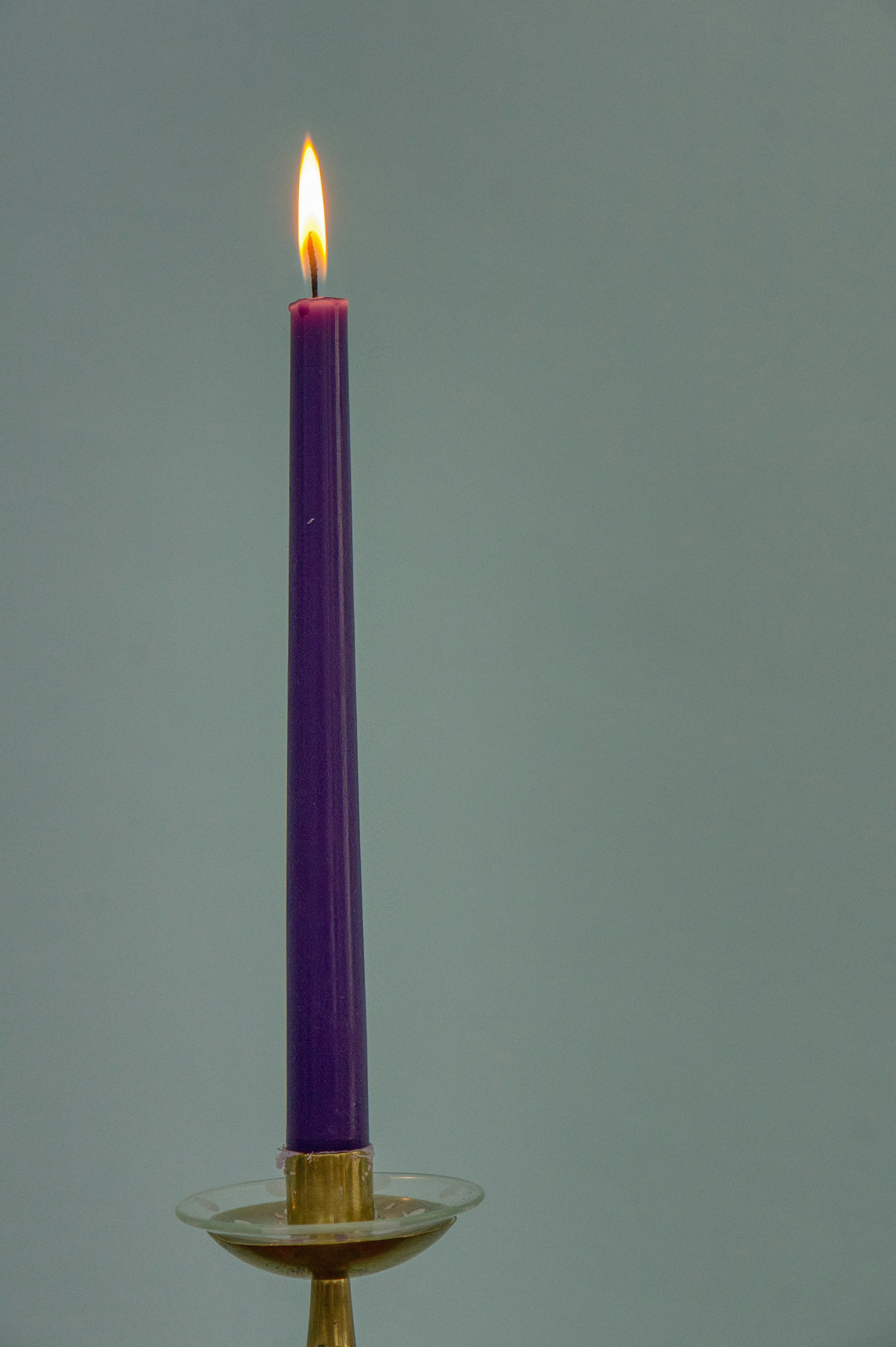 Solitary Violet Candle on Brass Stand Amid a Slate-Gray Backdrop