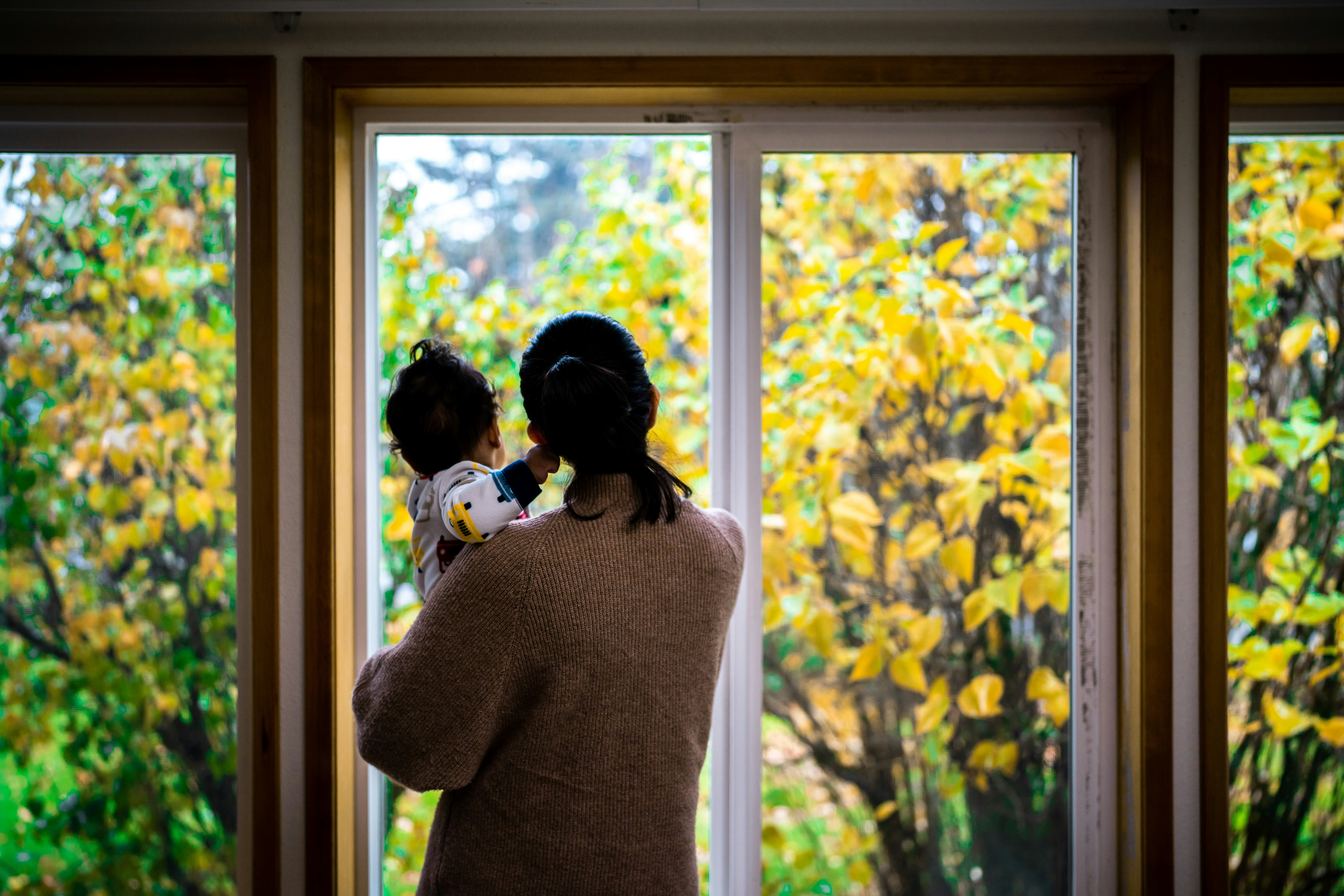 A woman holding a child looking out a window photo – Free Photo Image ...