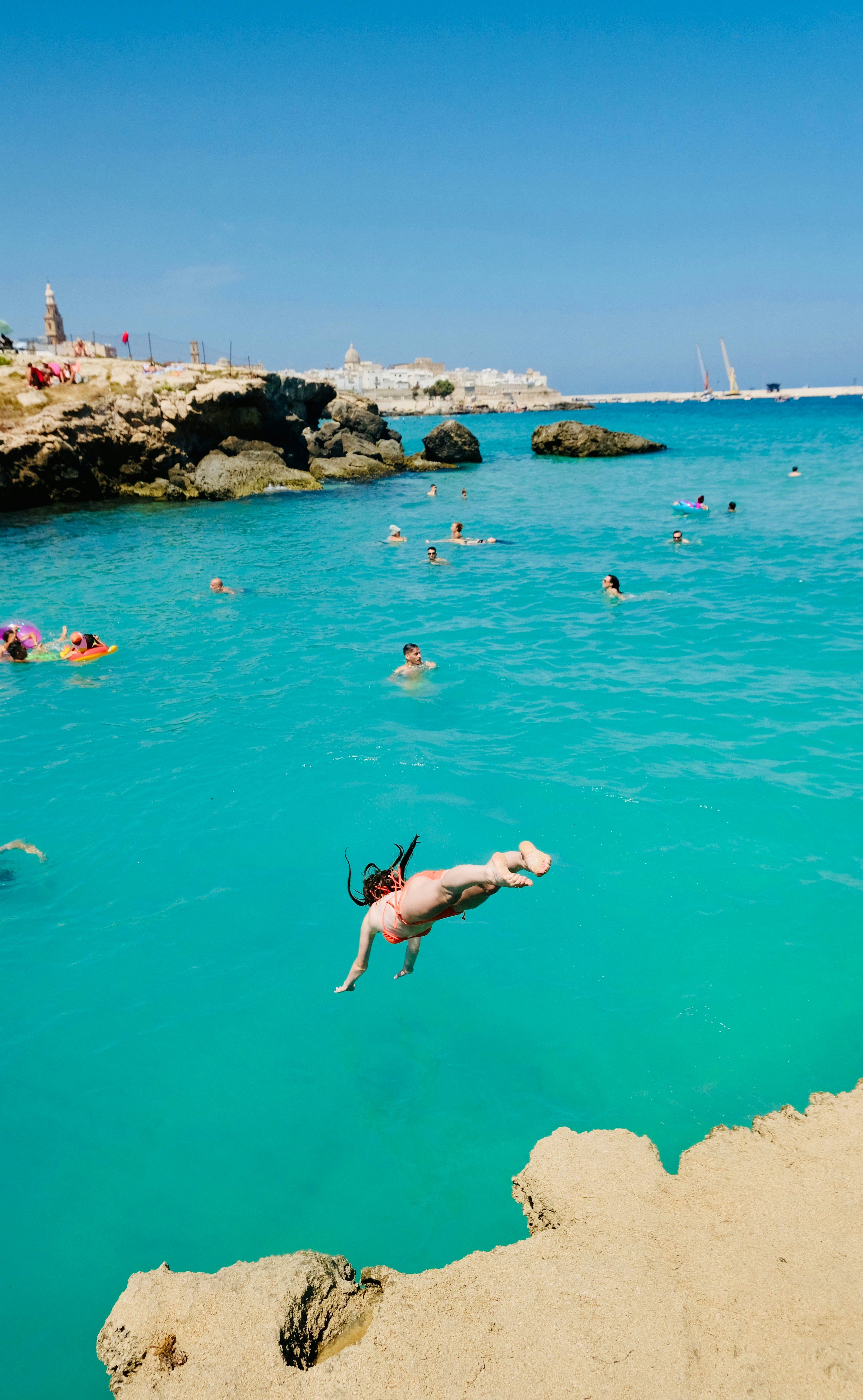 Azure Leap from the Rocks: A Diver Darts into Turquoise Waters