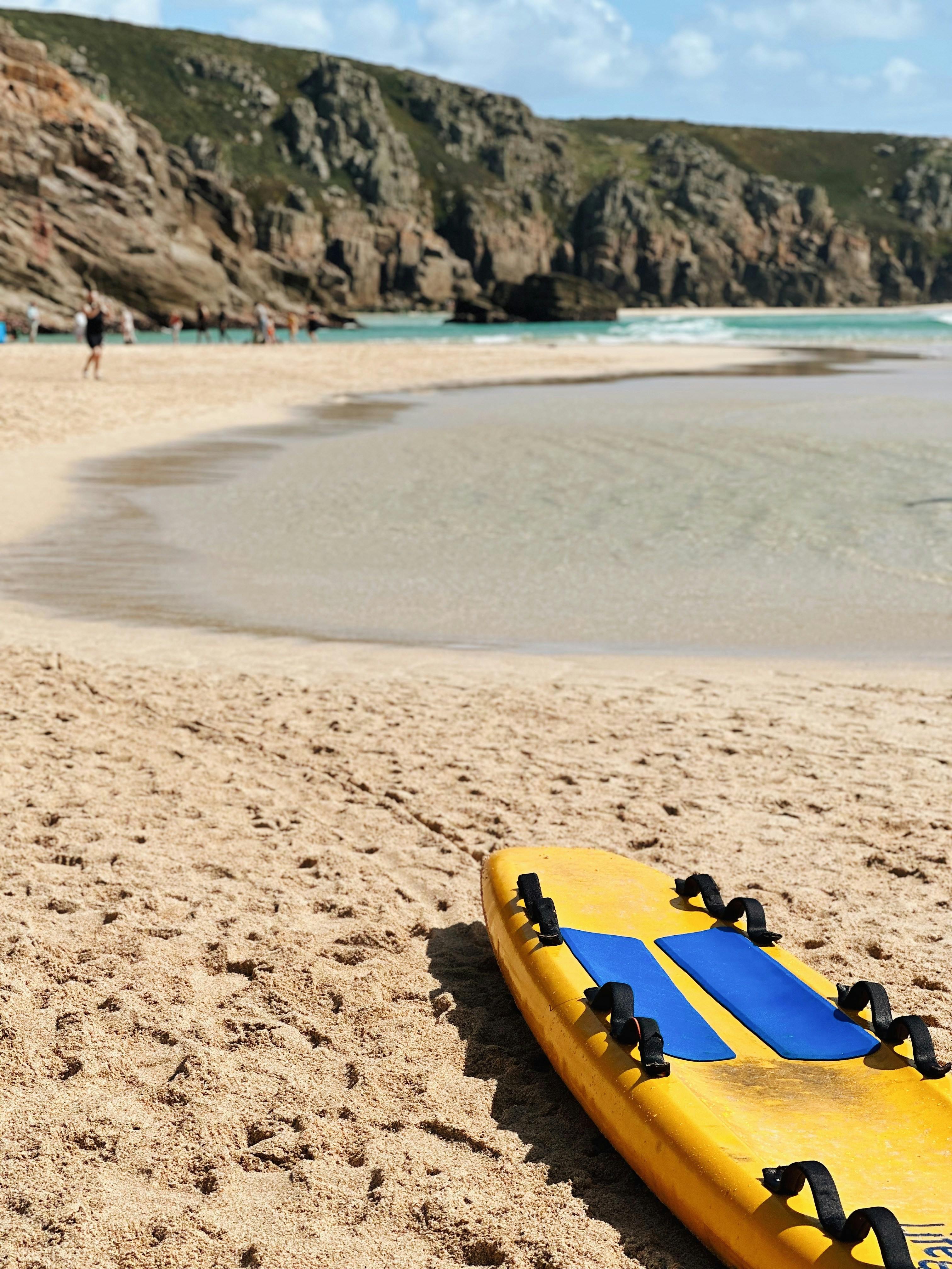 Yellow Boarder on Sunlit Beach with Rocky Cove