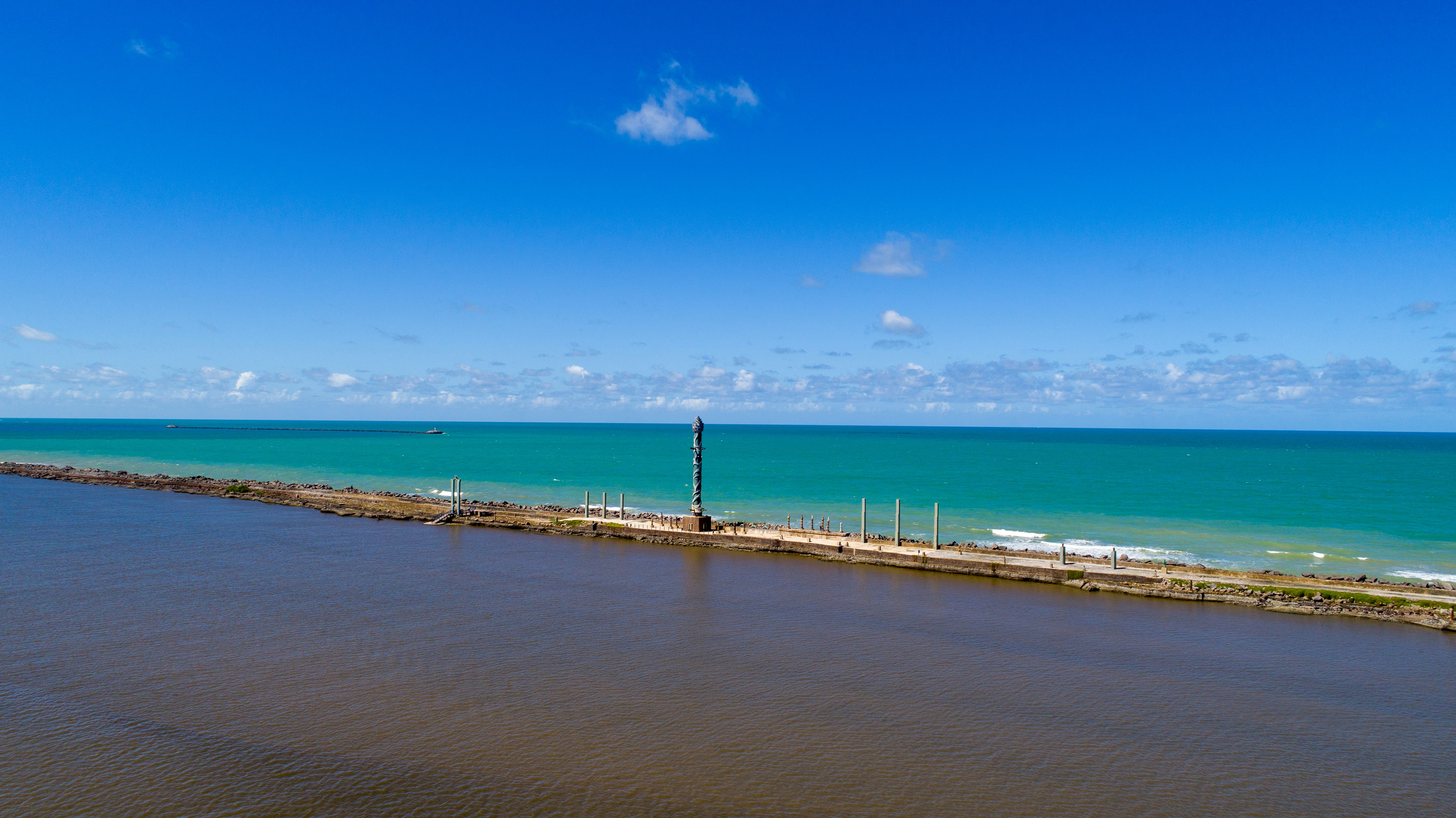 A large body of water sitting next to a beach photo – Free Brazil Image ...