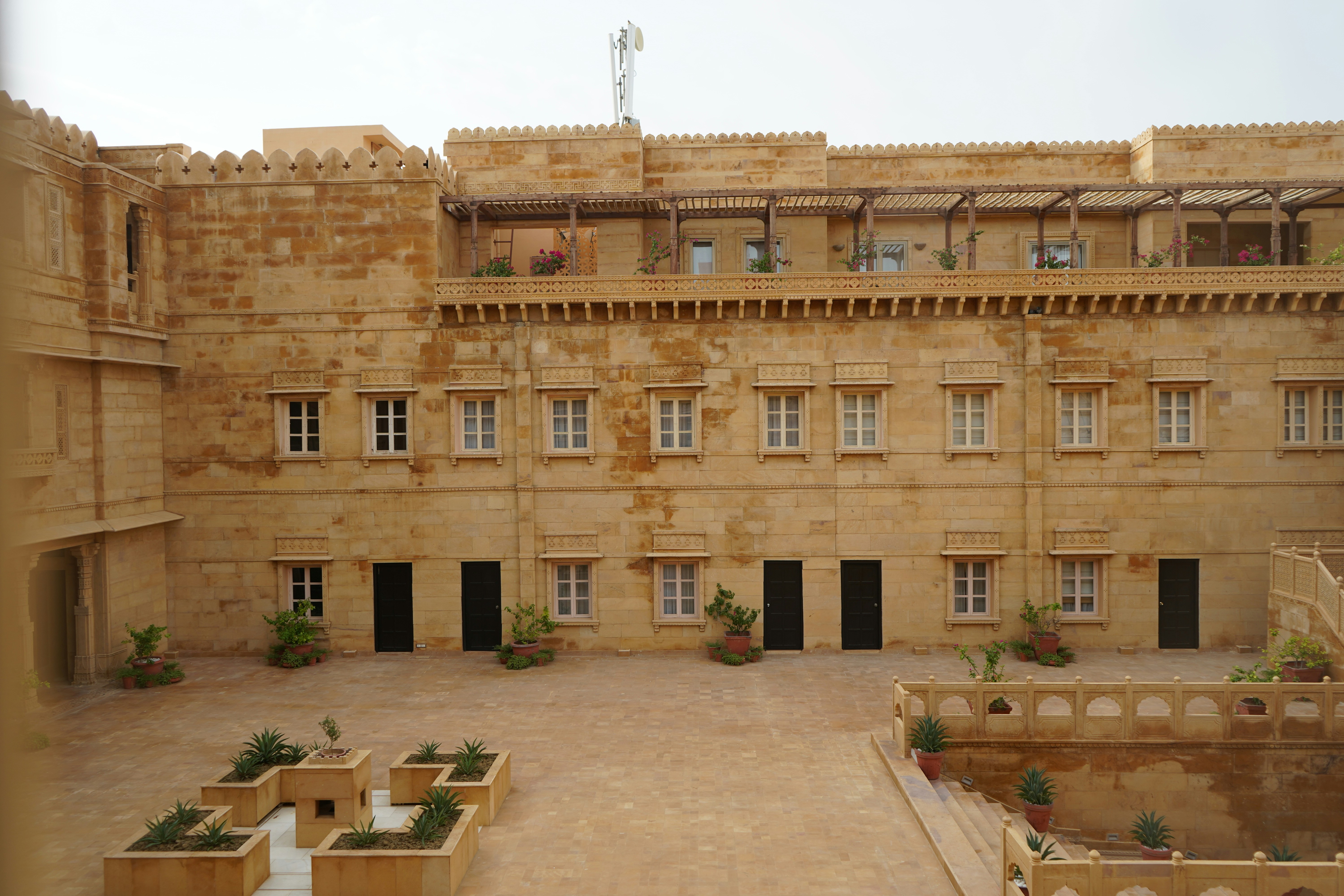 Historic sandstone courtyard with symmetrical architecture and multiple arched windows.