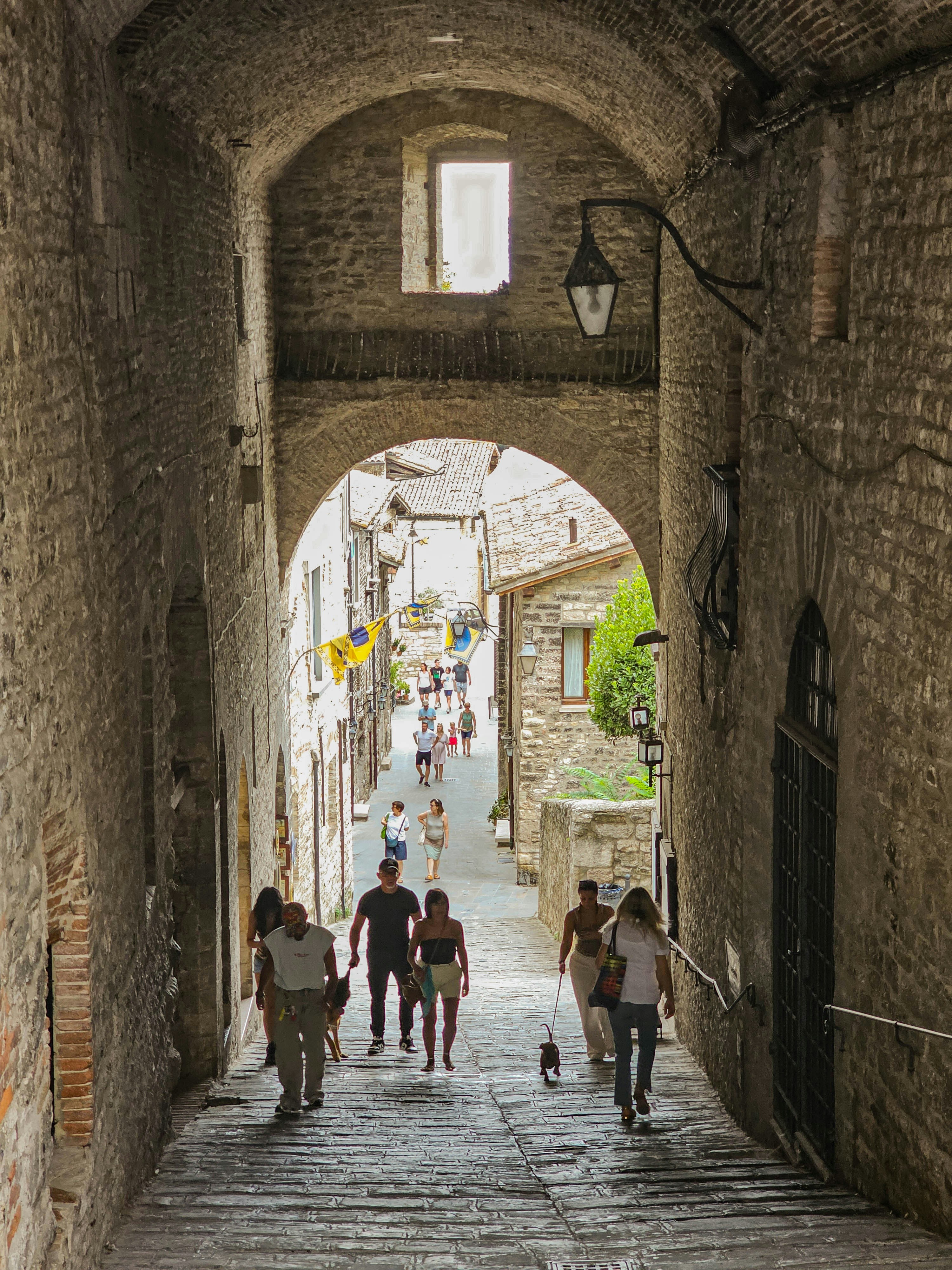 A group of people walking down a narrow alley way photo – Free Assisi ...