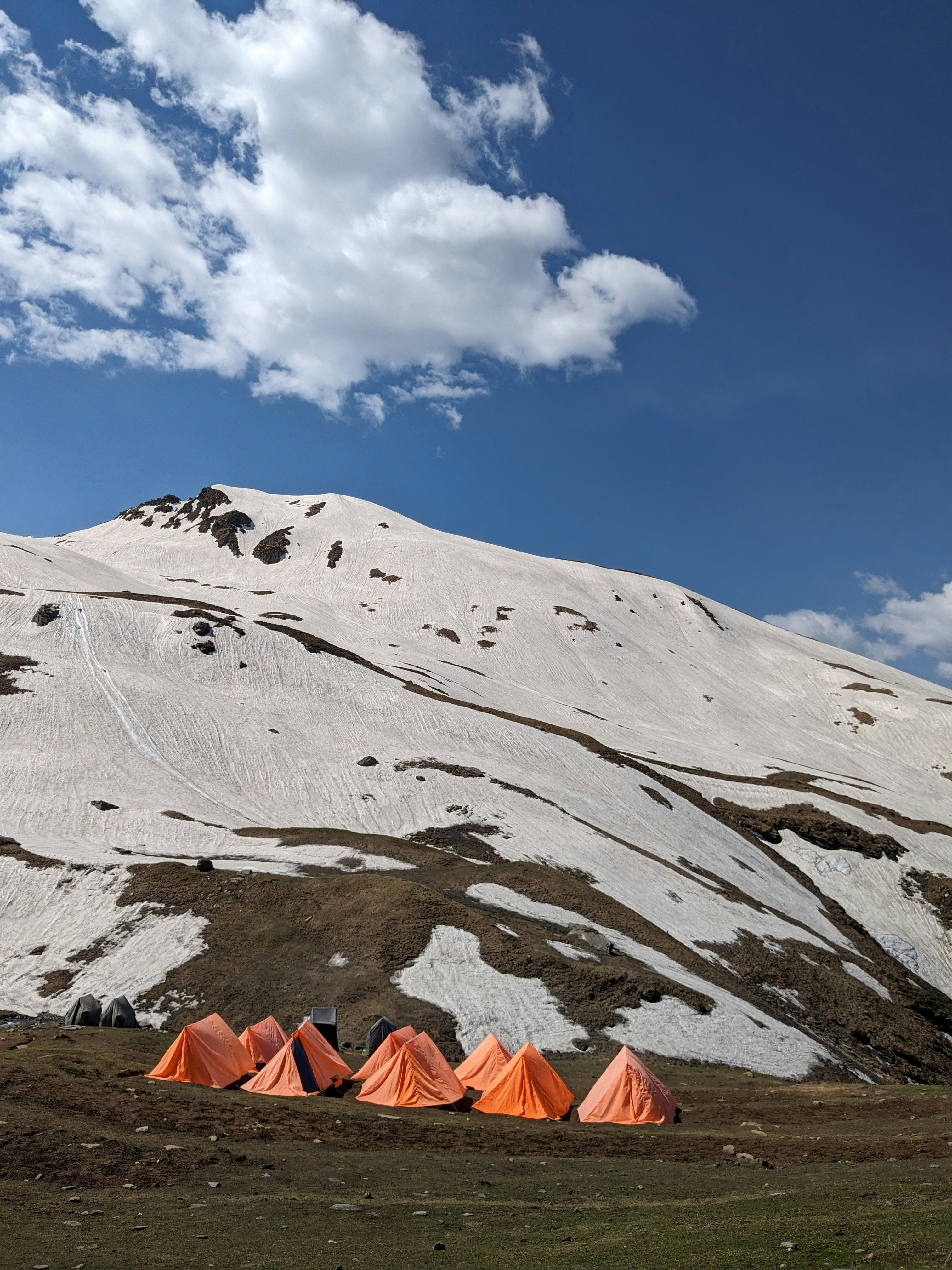 Row of Orange Tents Anchors a Snow-Dusted Alpine Camp