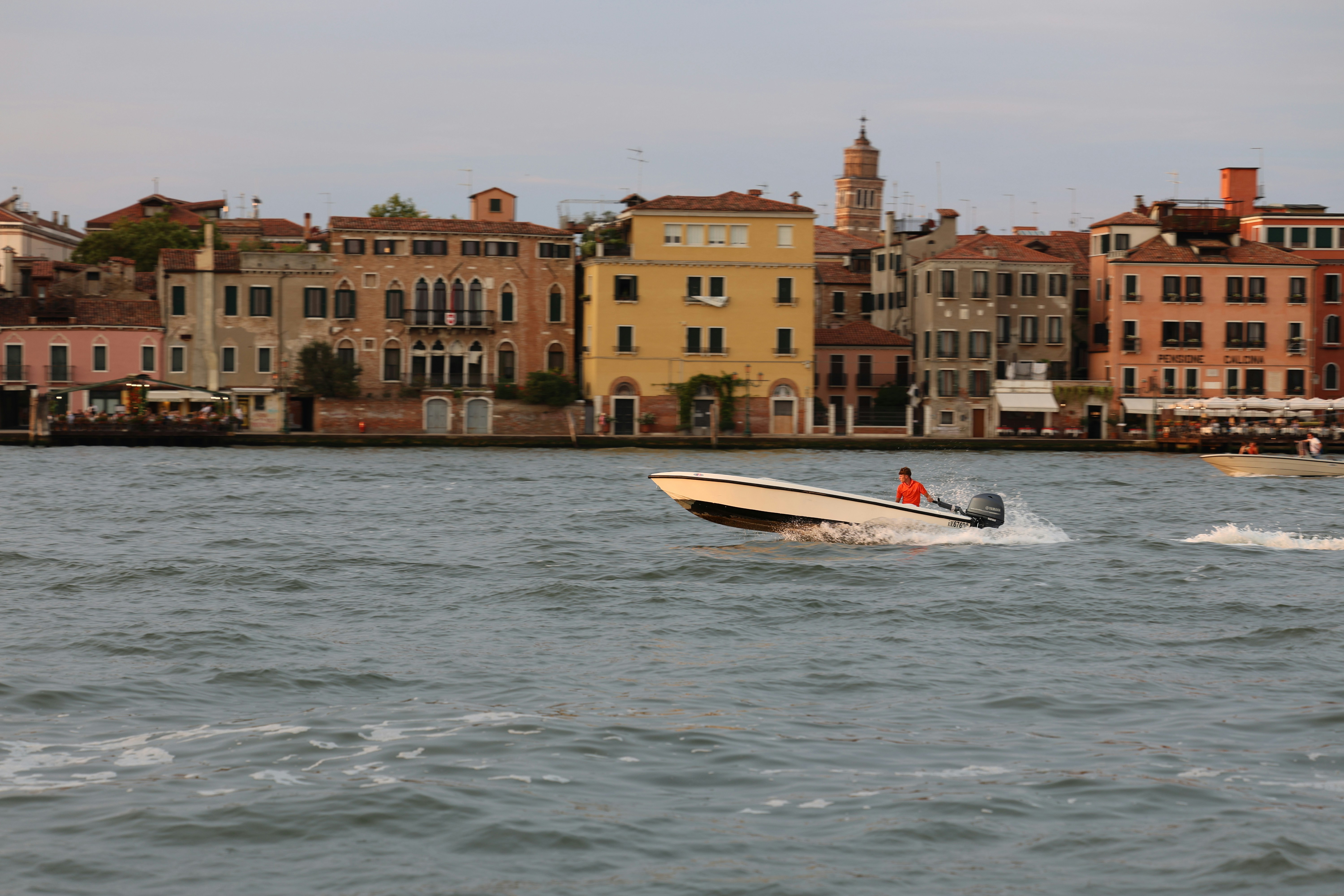 Sprint on the Adriatic: White speedboat cutting through a Venetian harbor