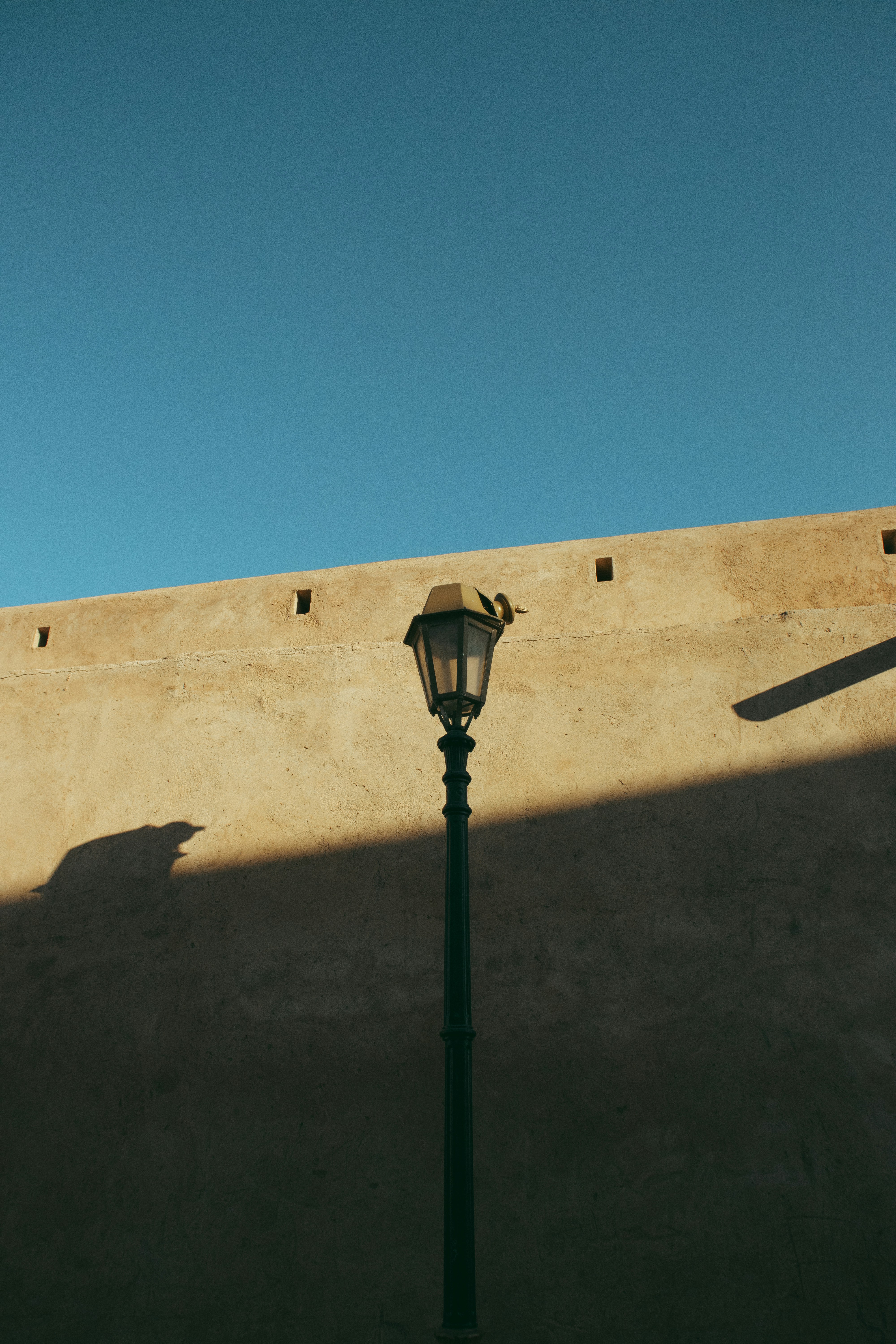 Lone Lamppost Against a Cerulean Sky and Sanded Wall